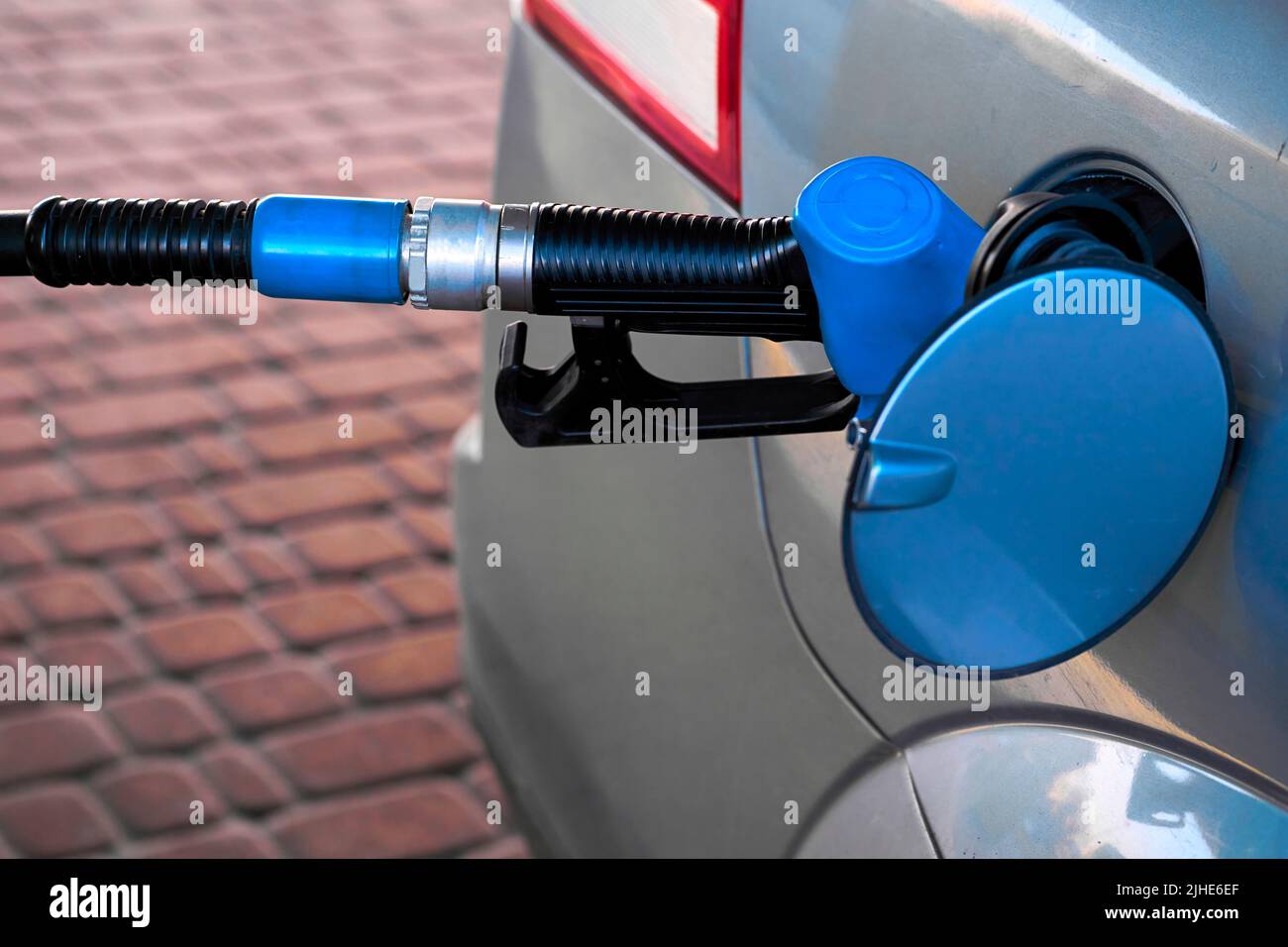 A refueling gun wakes up a gray car at a gas station Stock Photo - Alamy