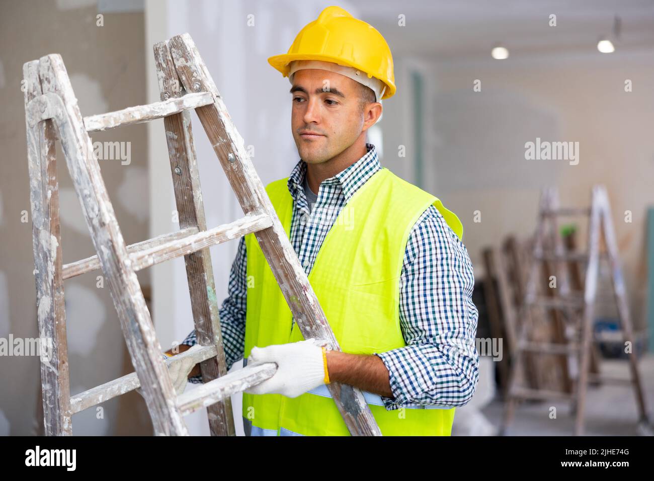 Construction worker carrying stepladder in apartment Stock Photo - Alamy