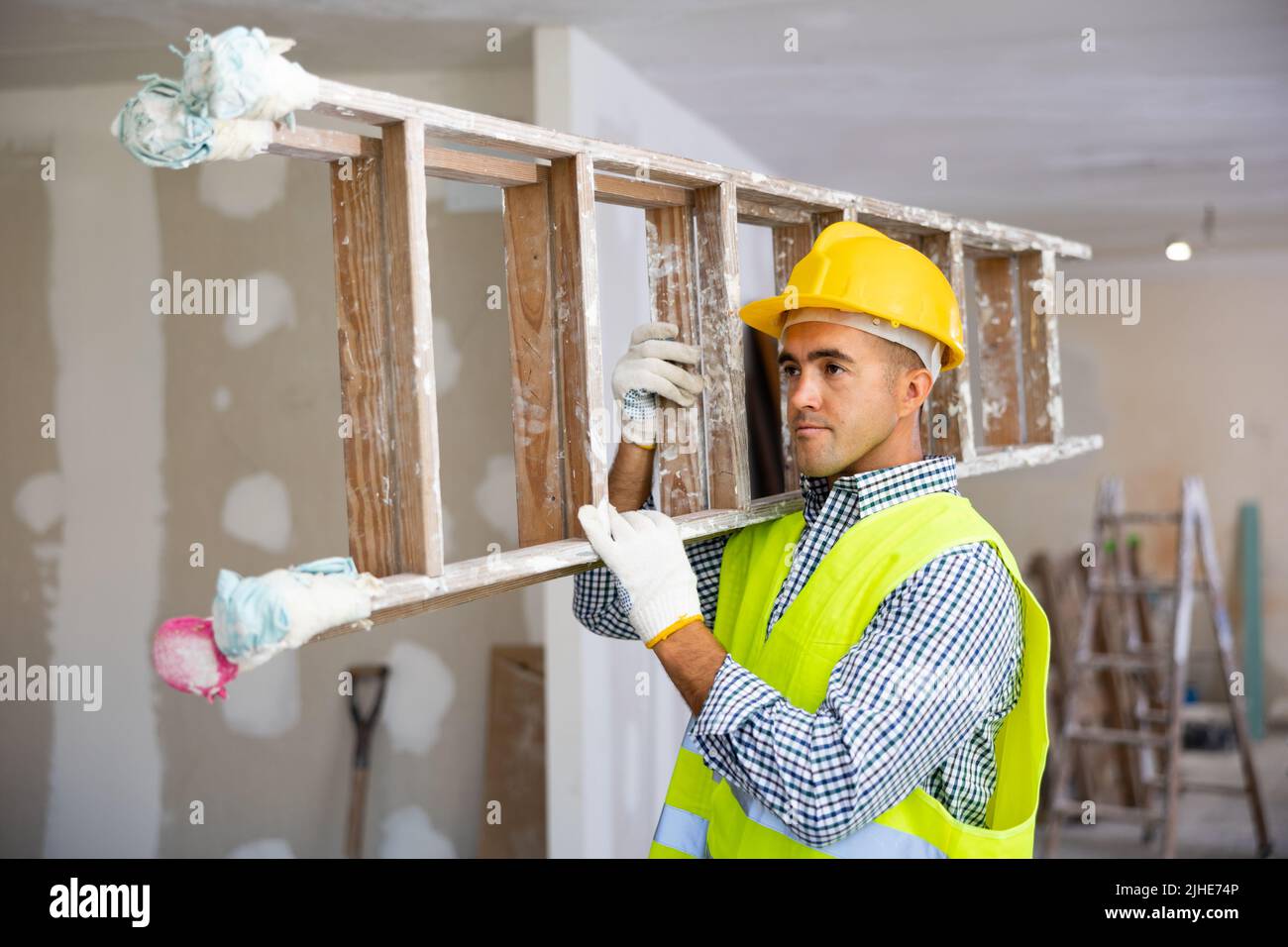 Construction worker carrying stepladder in apartment Stock Photo - Alamy