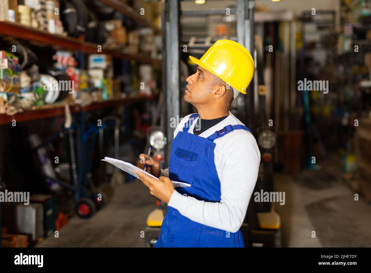 Focused salesman checking goods on shelves of construction hypermarket ...
