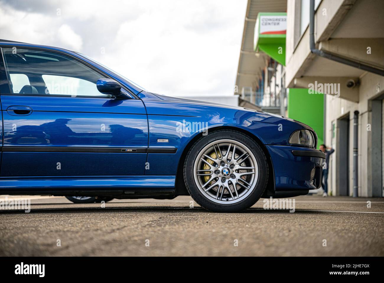A blue modern BMW car parked outdoors in daylight in cloudy sky ...