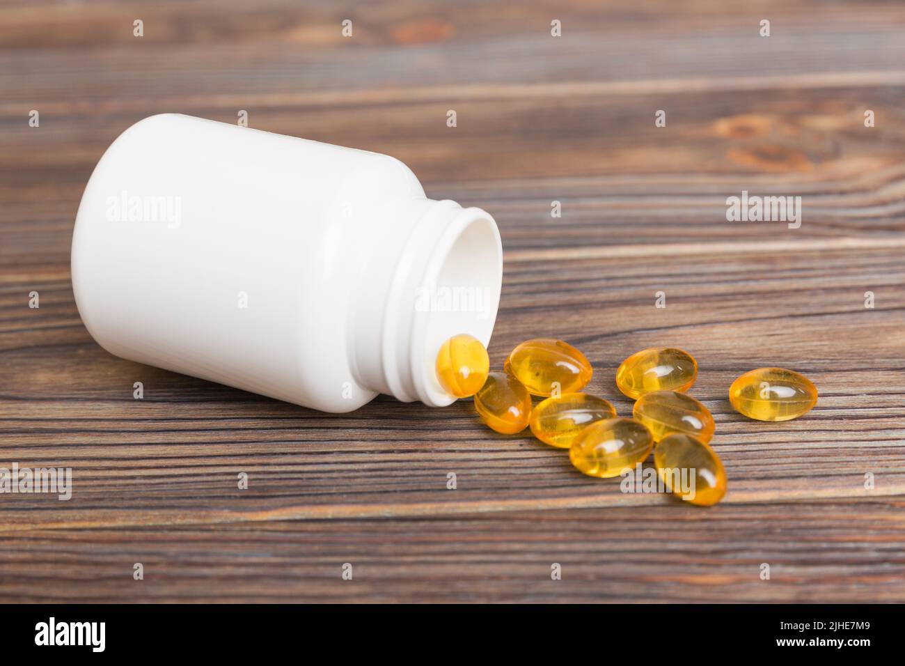 Omega-3 capsules lie in white bottle on a table background. Fish oil ...