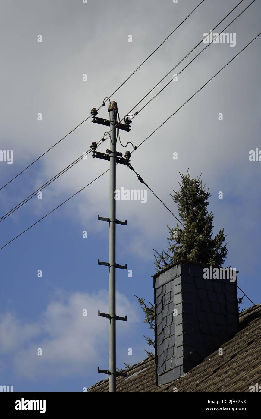 The vertical low-angle utility pole against the cloudy sky background ...