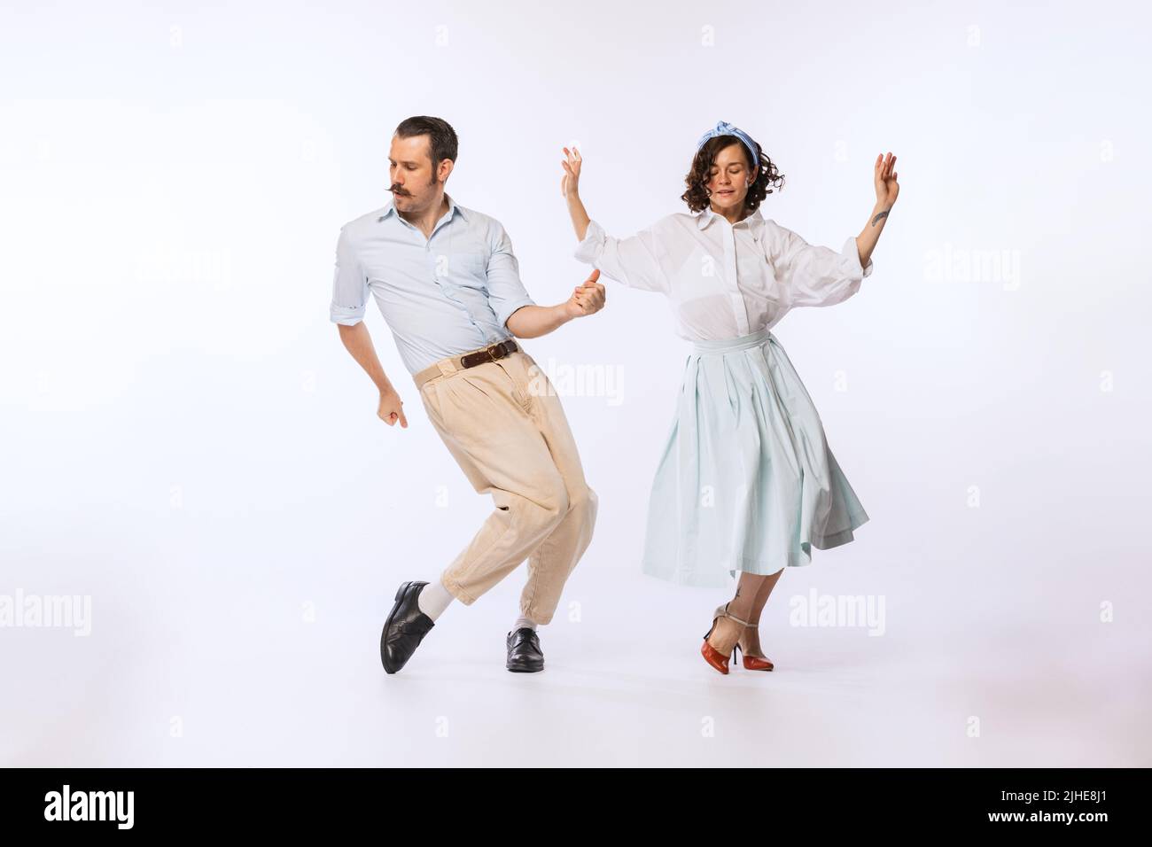 Portrait of young cheerful couple, man and woman, dancing isolated over ...