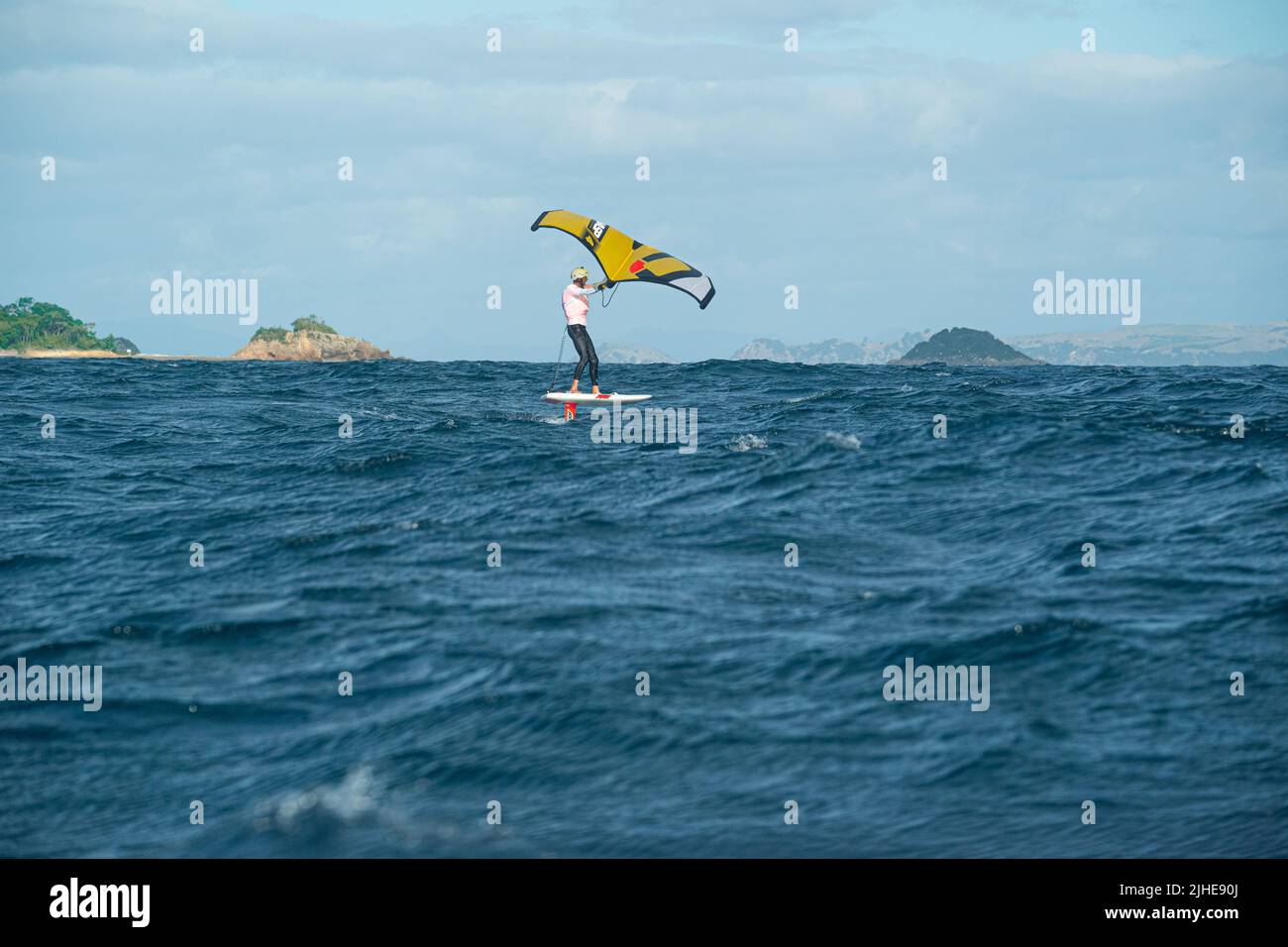 A man wing foils at sea using a hand held inflatable wing, riding a ...