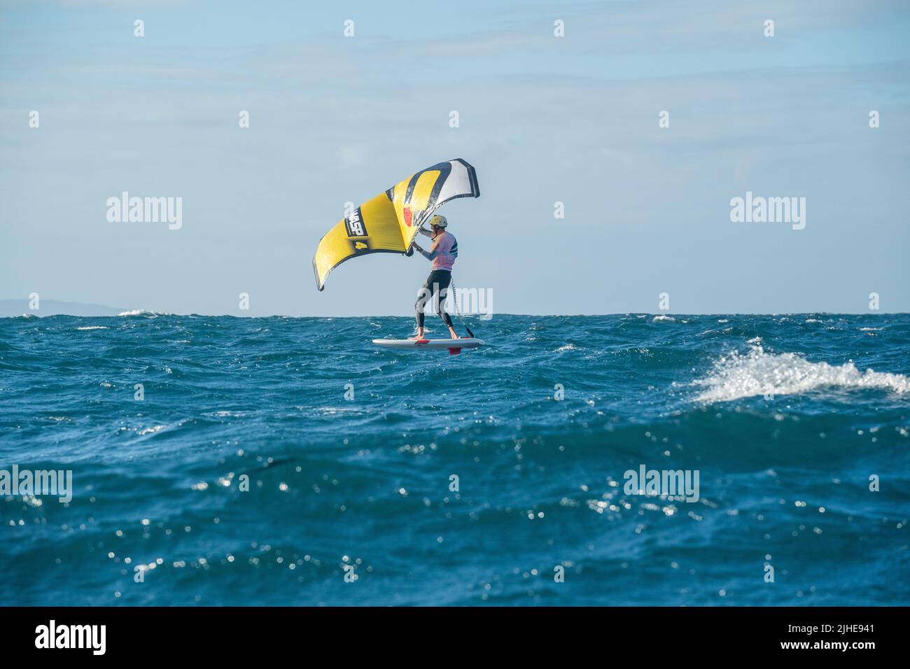 A man wing foils at sea using a hand held inflatable wing, riding a ...