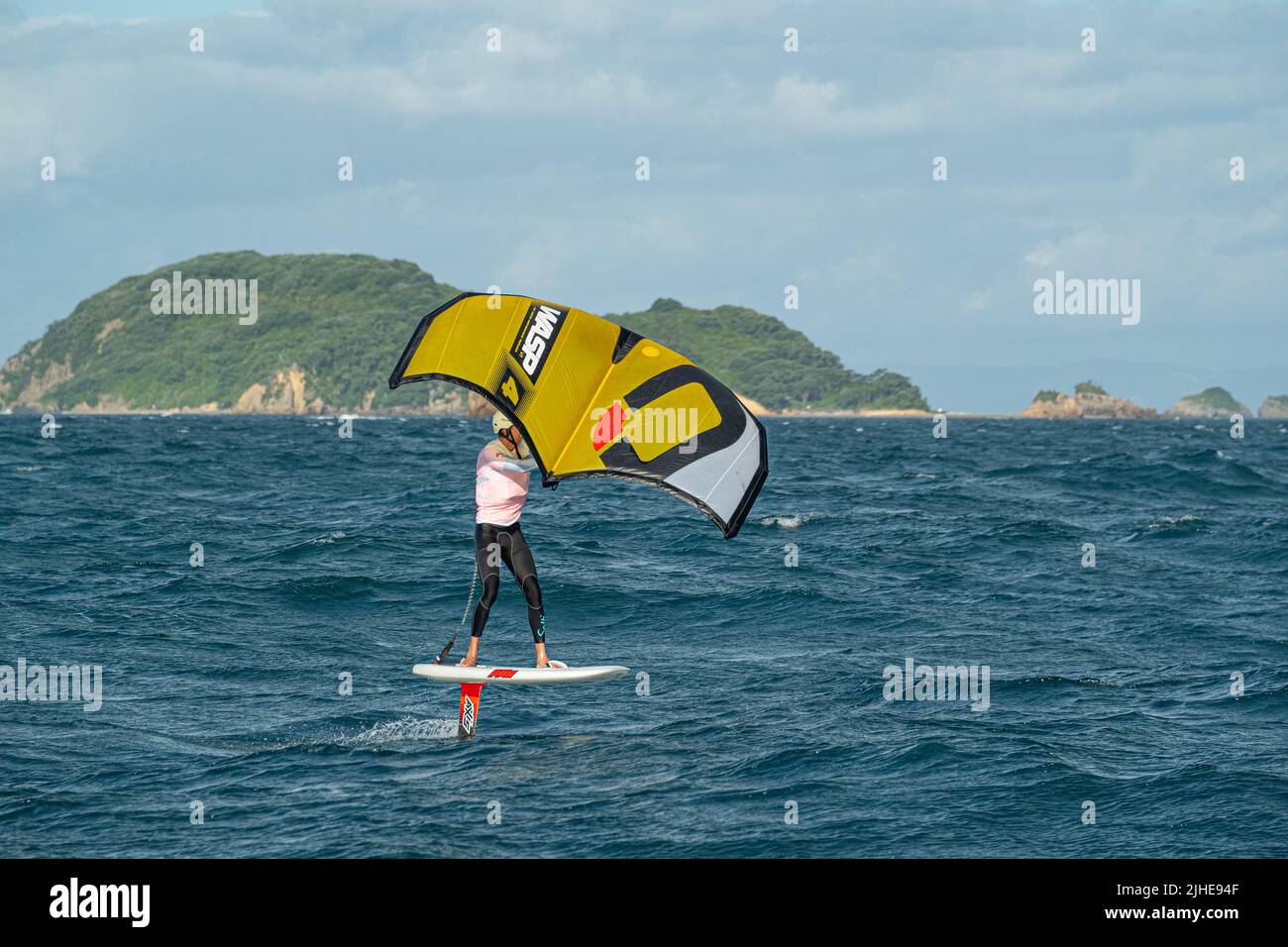 A man wing foils at sea using a hand held inflatable wing, riding a ...