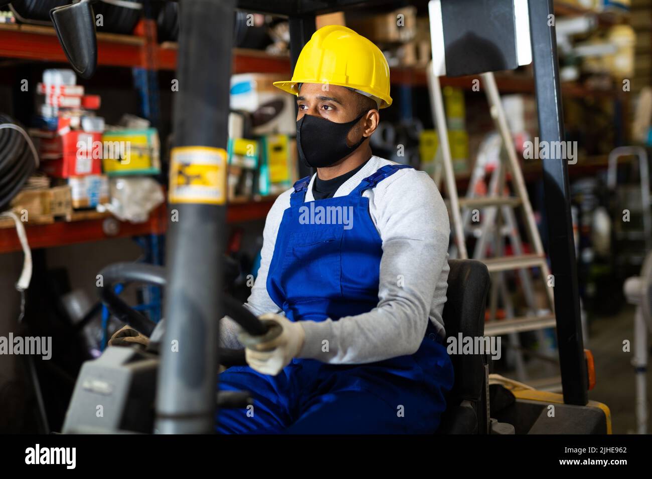 Operator of forklift wearing protective mask working in construction ...