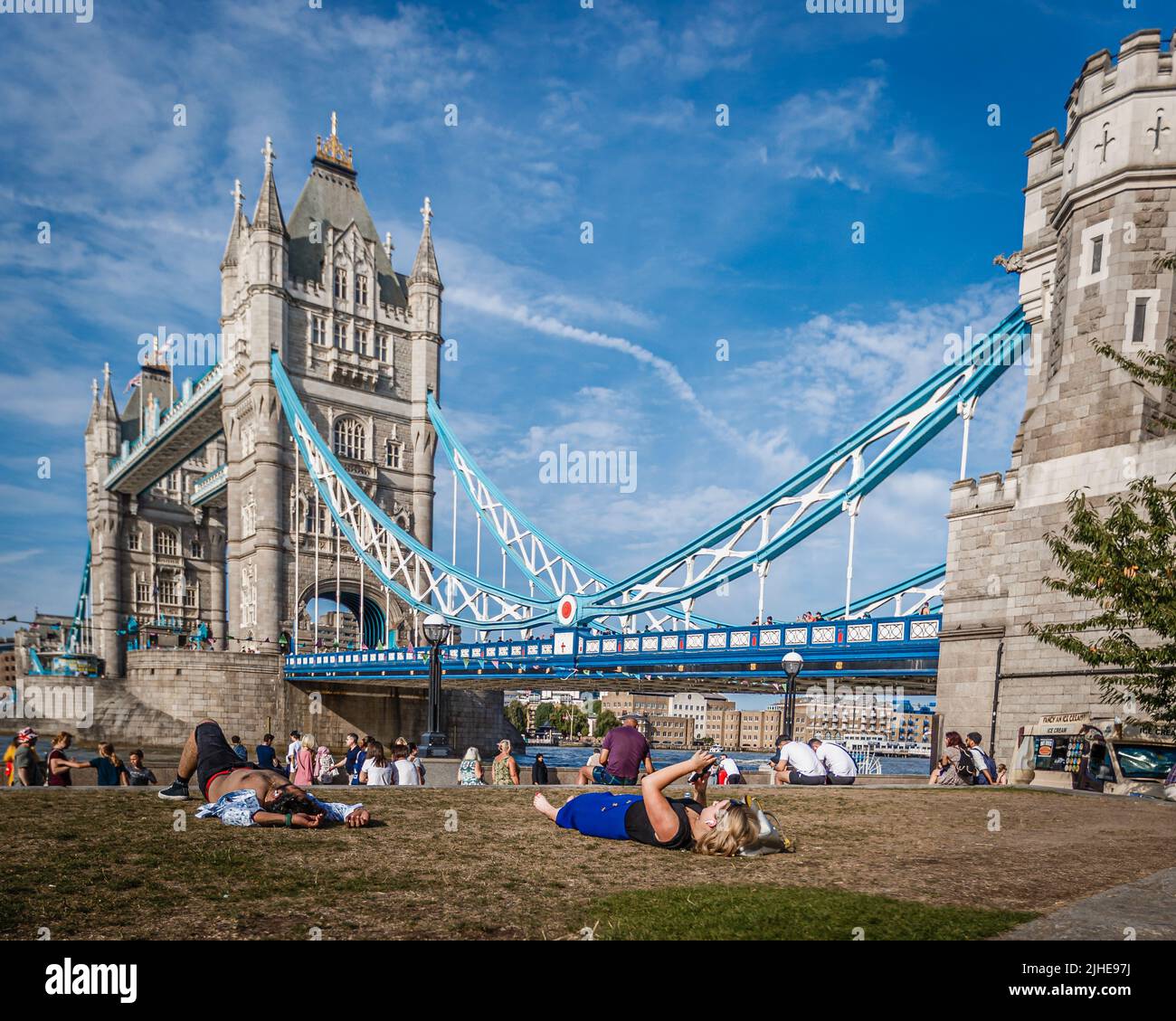 Londoners and tourists enjoy the heatwave by sunbathing by Tower Bridge ...