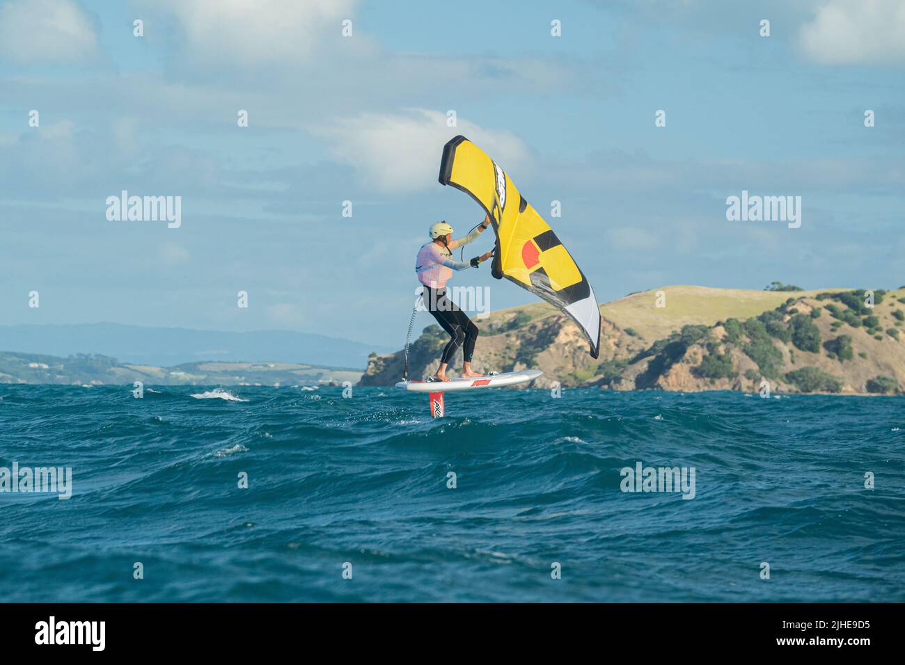 A man wing foils at sea using a hand held inflatable wing, riding a ...