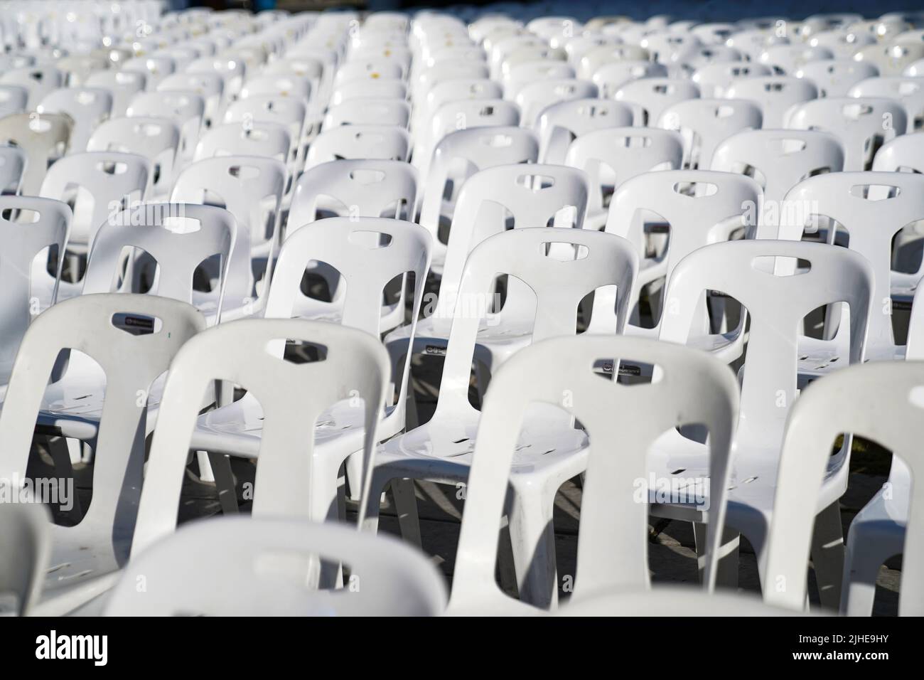 Many white plastic chairs were set up in a square area with the row and ...