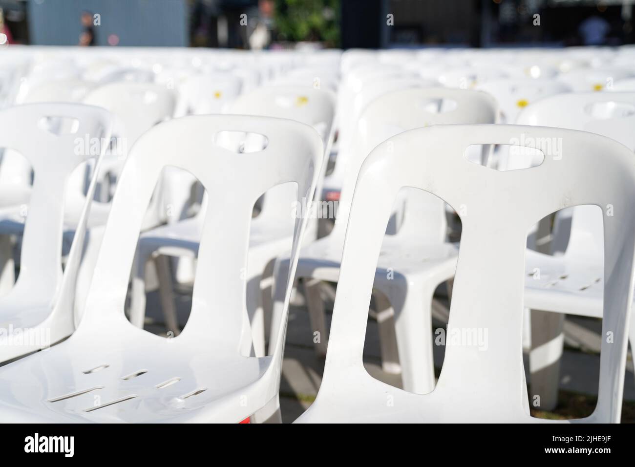 Many white plastic chairs were set up in a square area with the row and ...