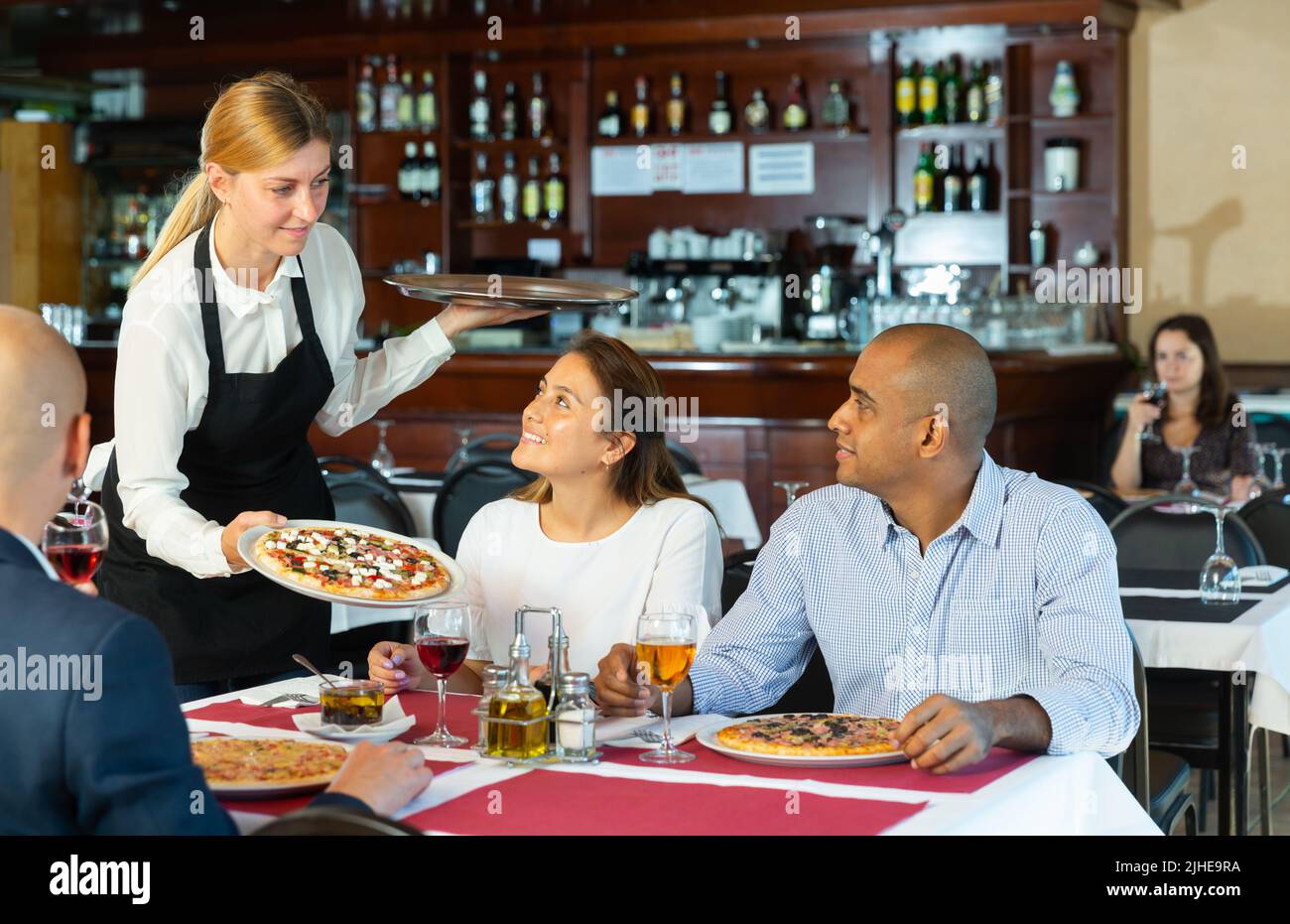 Waitress brought delicious pizza to restaurant guests Stock Photo - Alamy