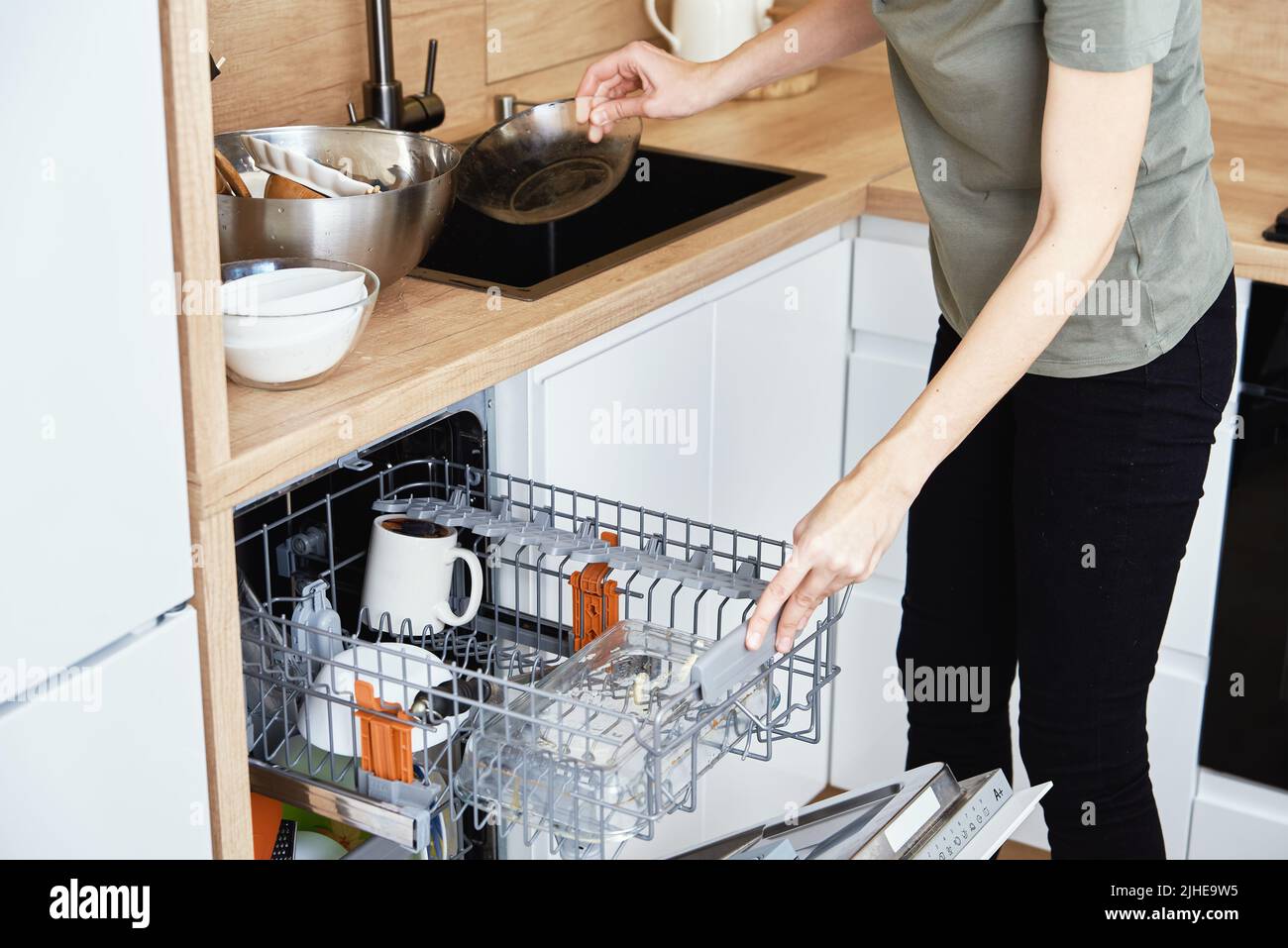 Woman load dirty dishes into open dishware, Modern kitchen appliance ...