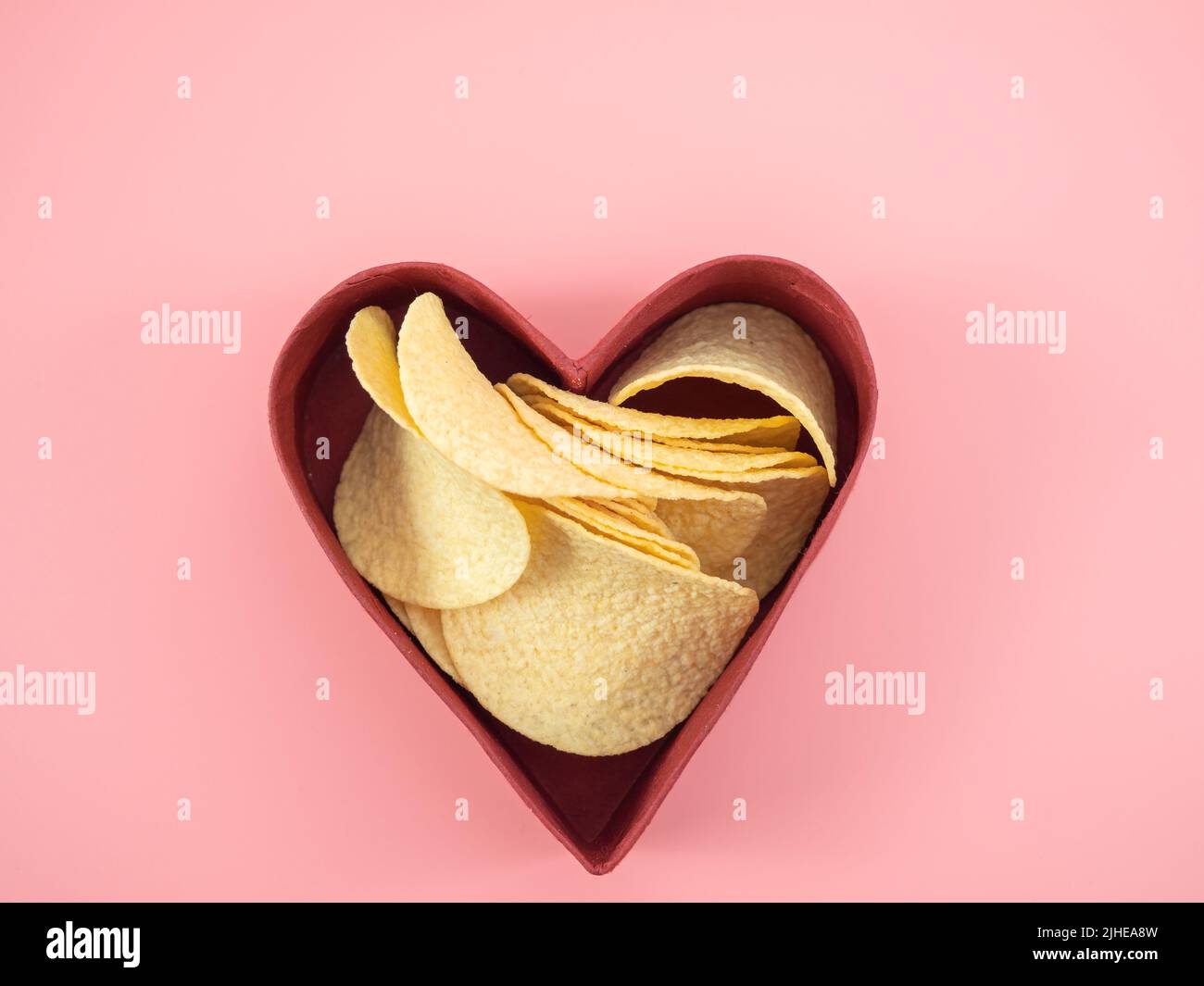 Chips in a box in the shape of a heart on a pink background. Chips in a ...