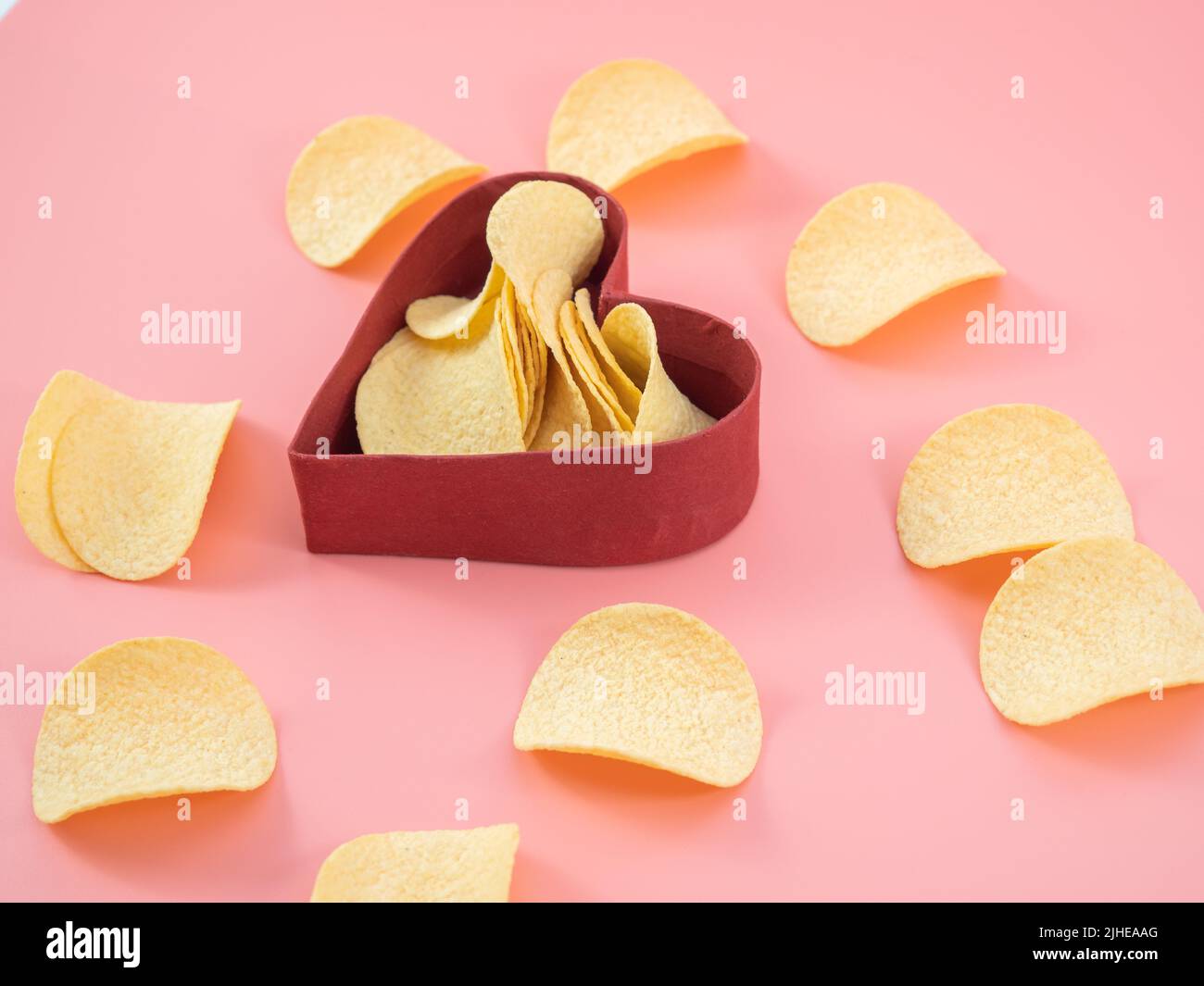 Chips in a box in the shape of a heart on a pink background. Chips in a ...