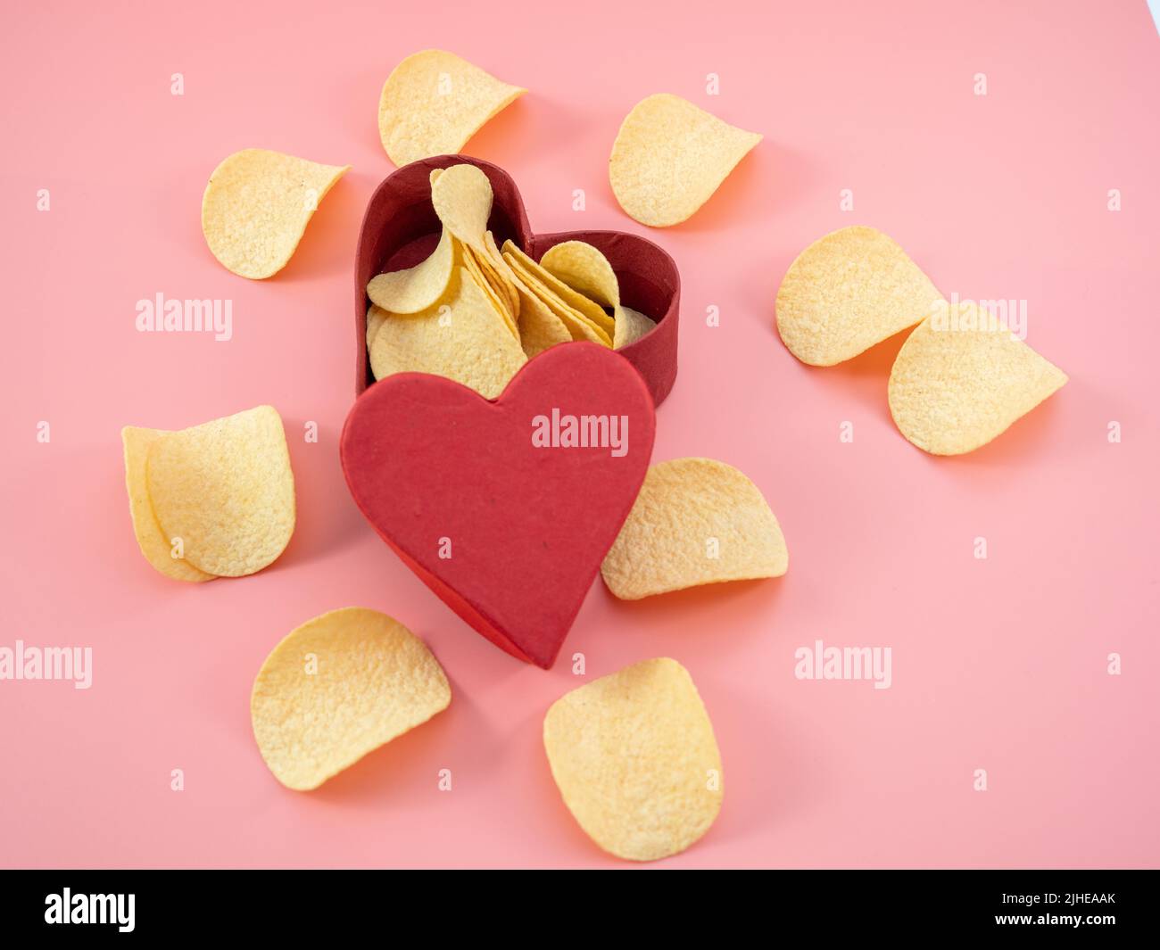 Chips in a box in the shape of a heart on a pink background. Chips in a ...