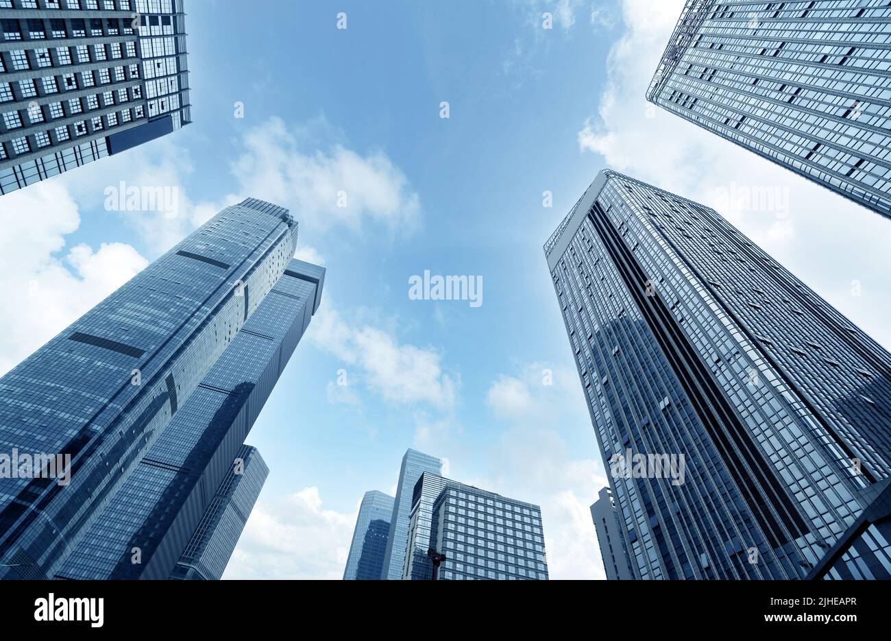 Bottom view of modern skyscrapers in business district against blue sky ...