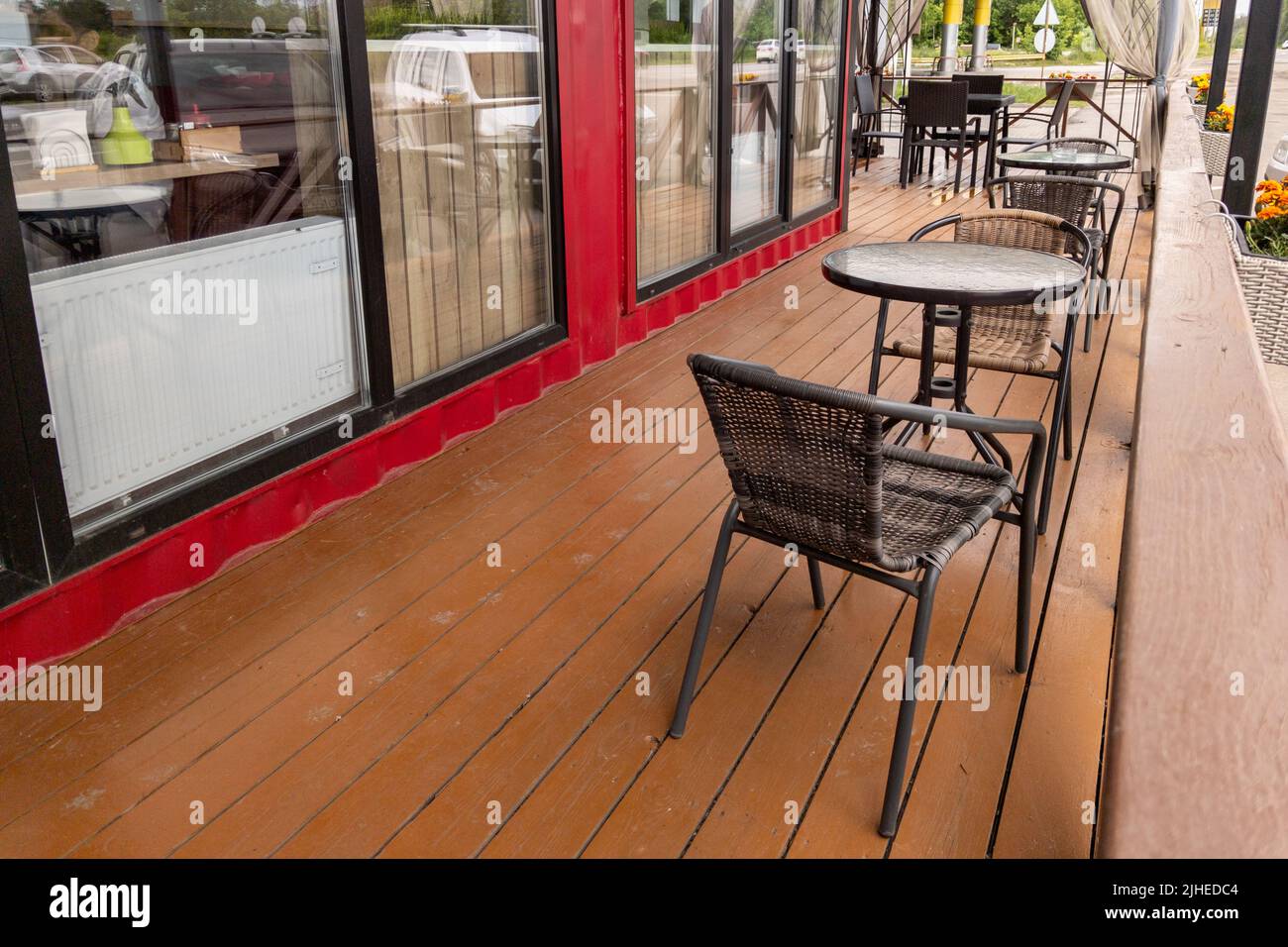 row of wicker chairs and glass tables near windows of roadside cafe ...