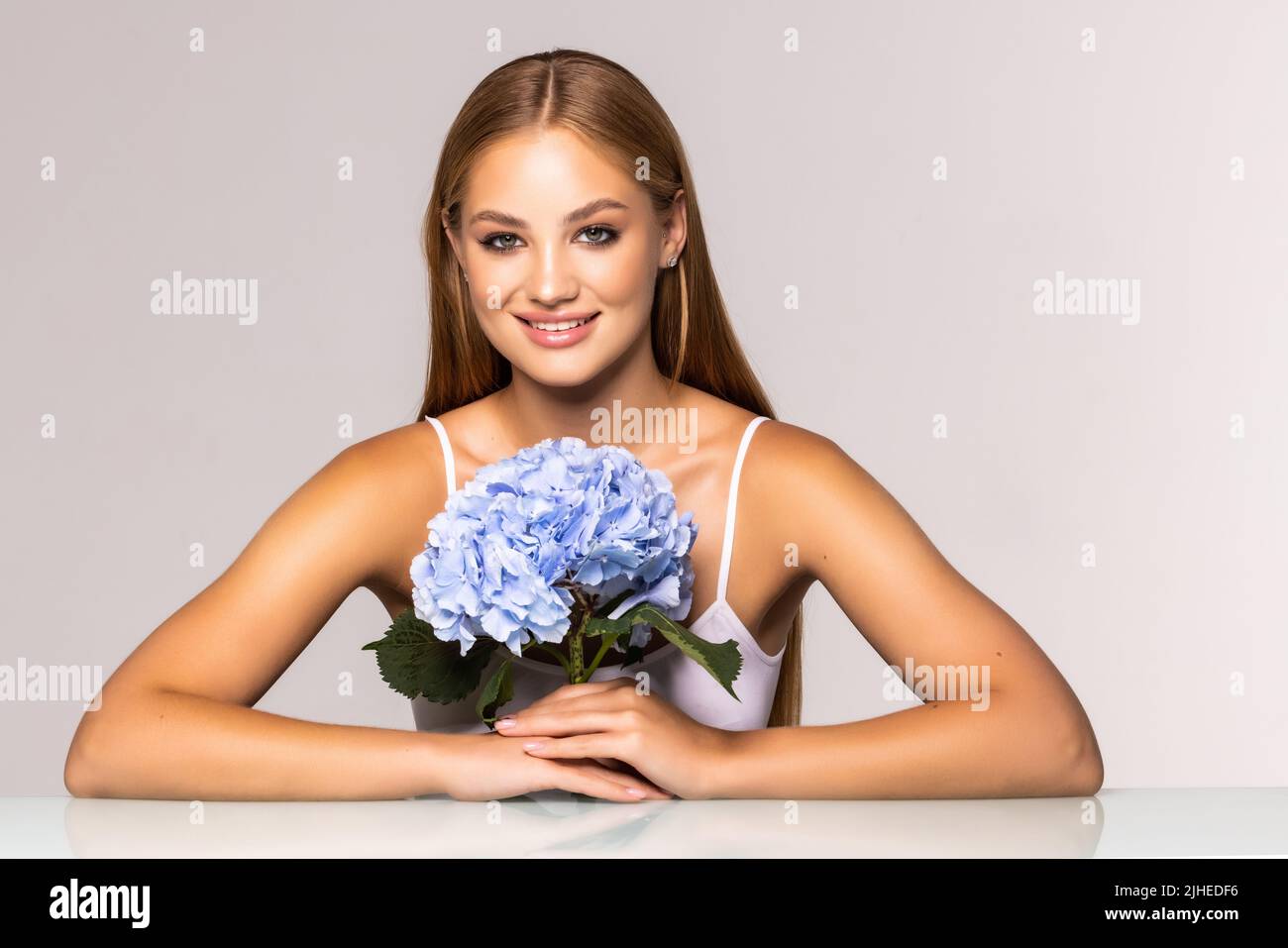 Beautiful young woman holding blue flower at face, isolated on white ...