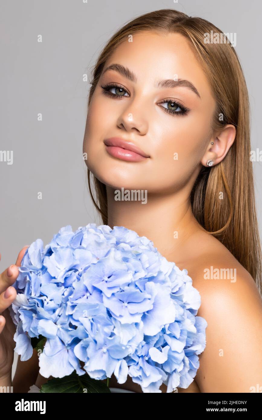 Beautiful young woman holding blue flower at face, isolated on white ...