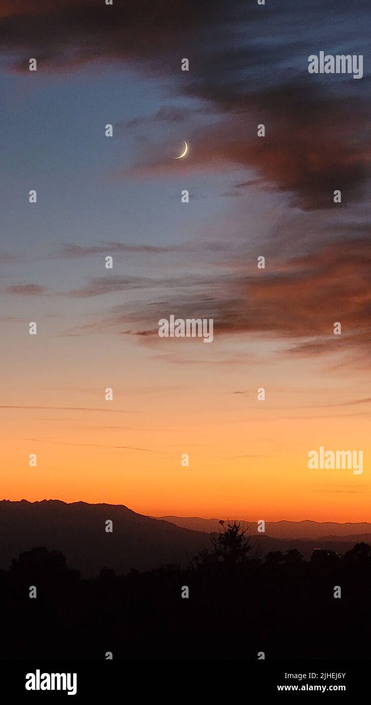 A vertical shot of the dramatic sunset with the moon crescent in Lovell ...