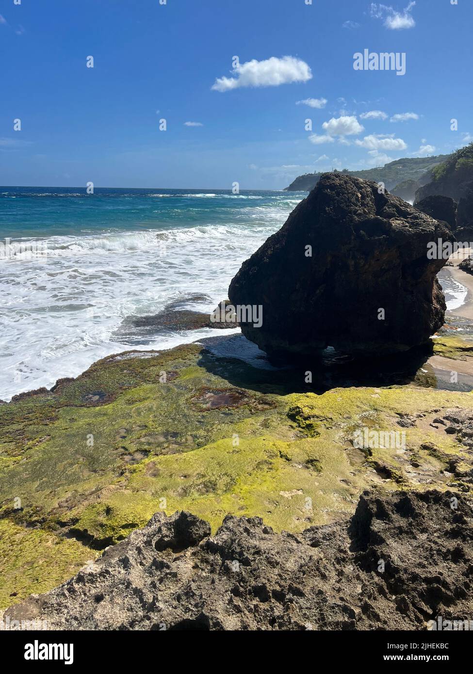The sea waves crashing into a rock formation near the algal shore on ...