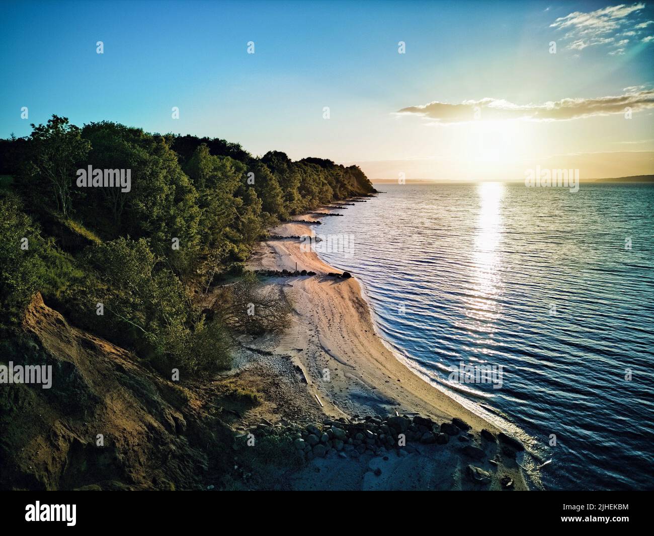 An aerial view of lush green cliffs over the sandy beach with the ...