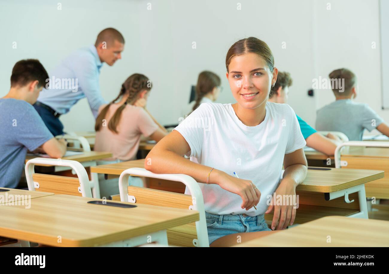 Smiling girl high school student listening to teacher during lesson ...