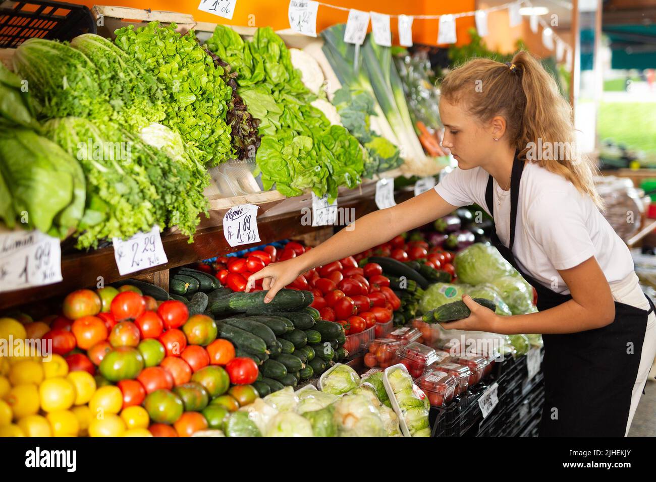 Teenage girl working in grocery, selling cucumber Stock Photo - Alamy