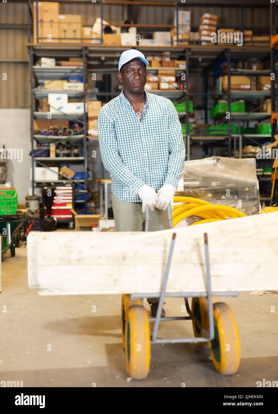 Warehouse worker pushing cart with planks Stock Photo - Alamy