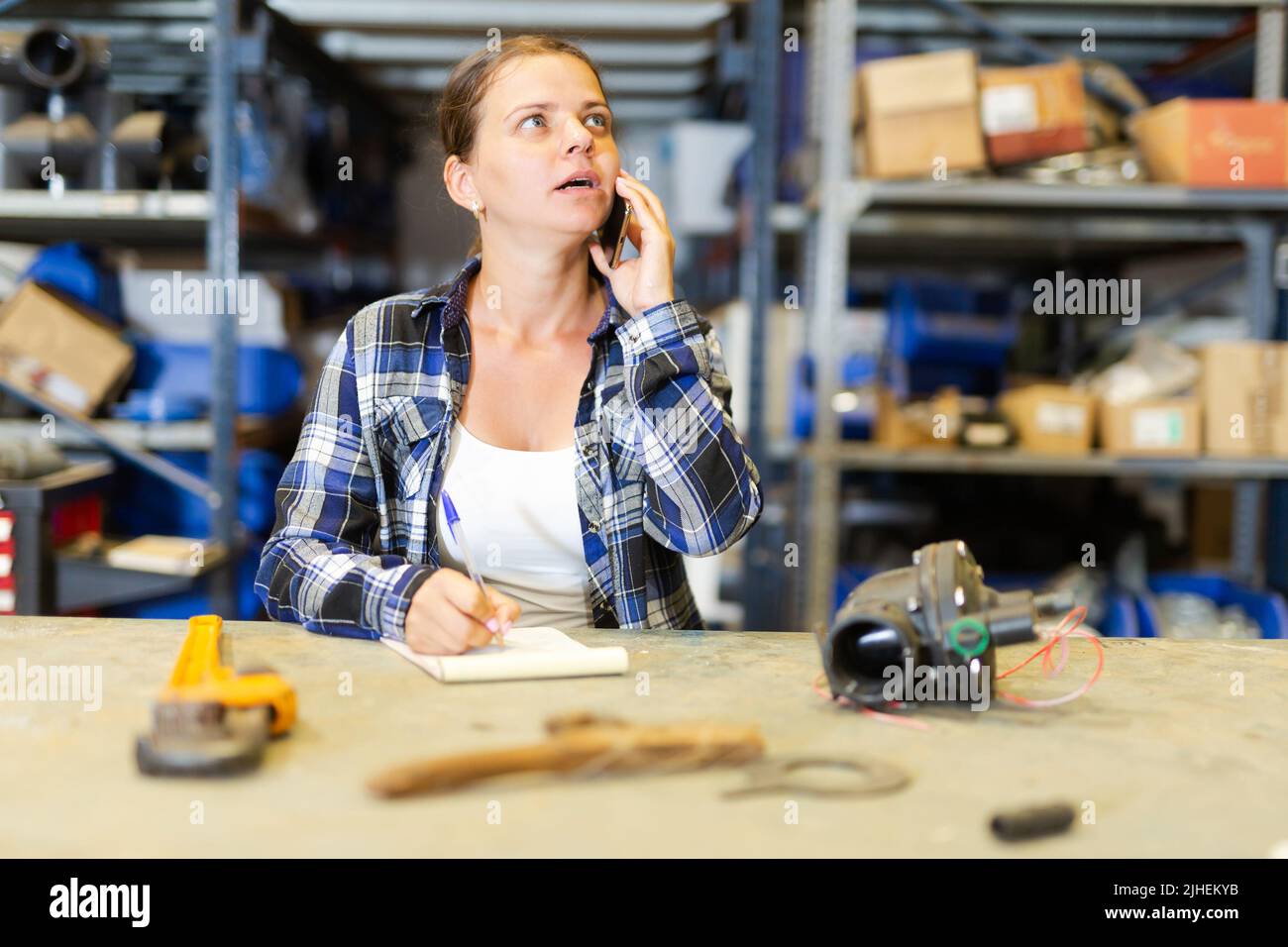 Woman store warehouse employee talking on mobile phone with customer ...