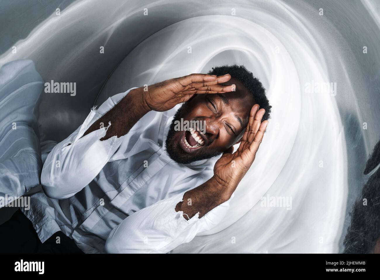 Young black man holding his head and screaming isolated over metal wall ...