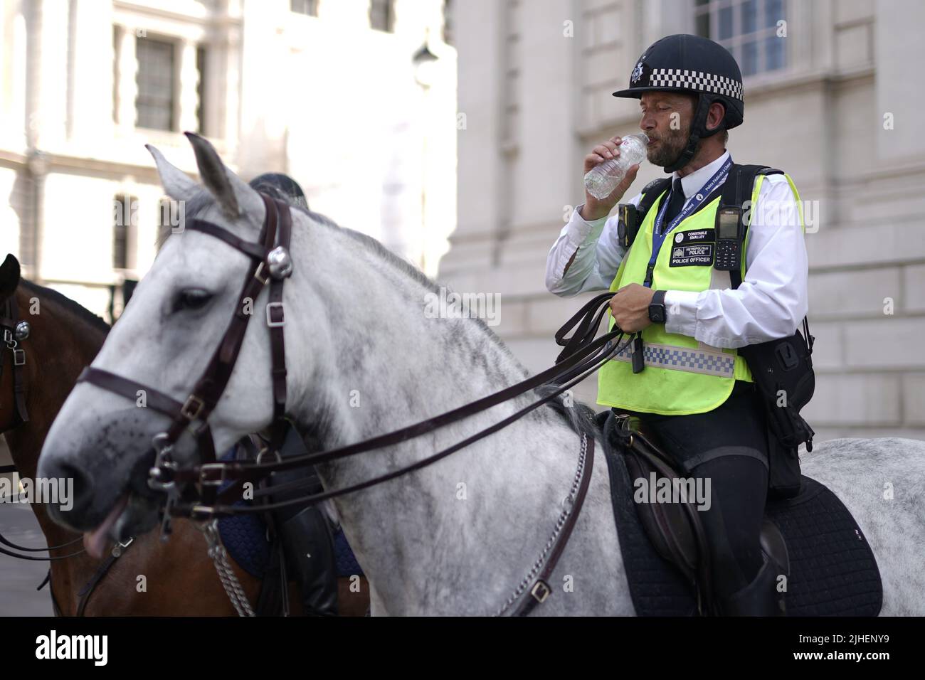 A police officer drinking water whilst on a police horse on Whitehall ...
