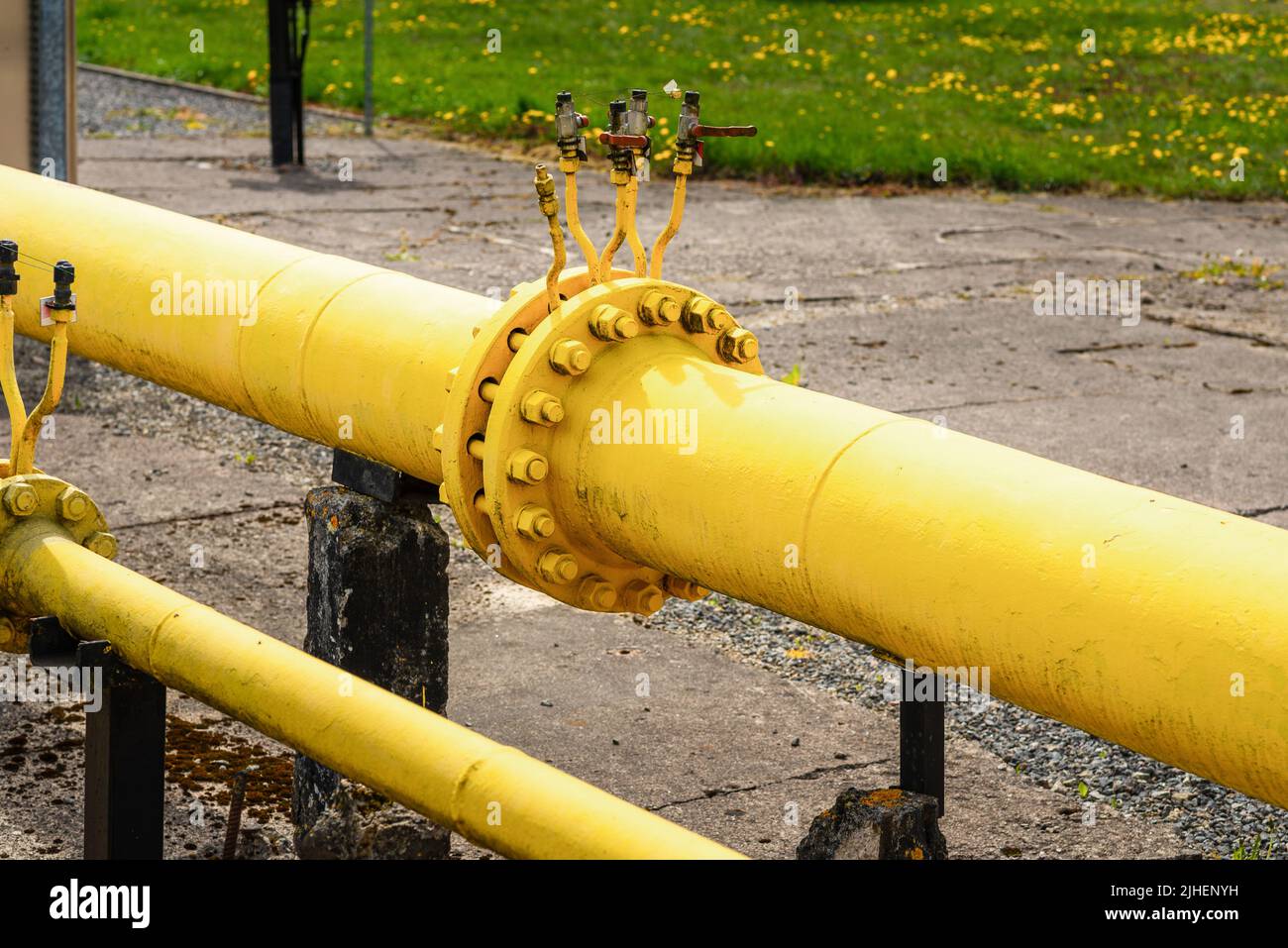 Two black and yellow gas pipes are connected by large bolts.Background ...