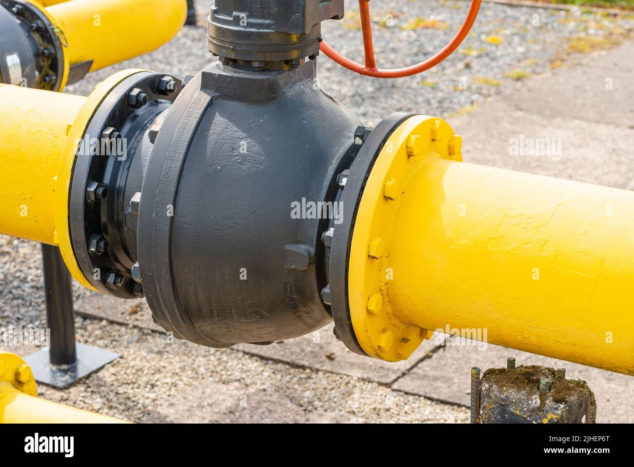 Two black and yellow gas pipes are connected by large bolts.Background ...