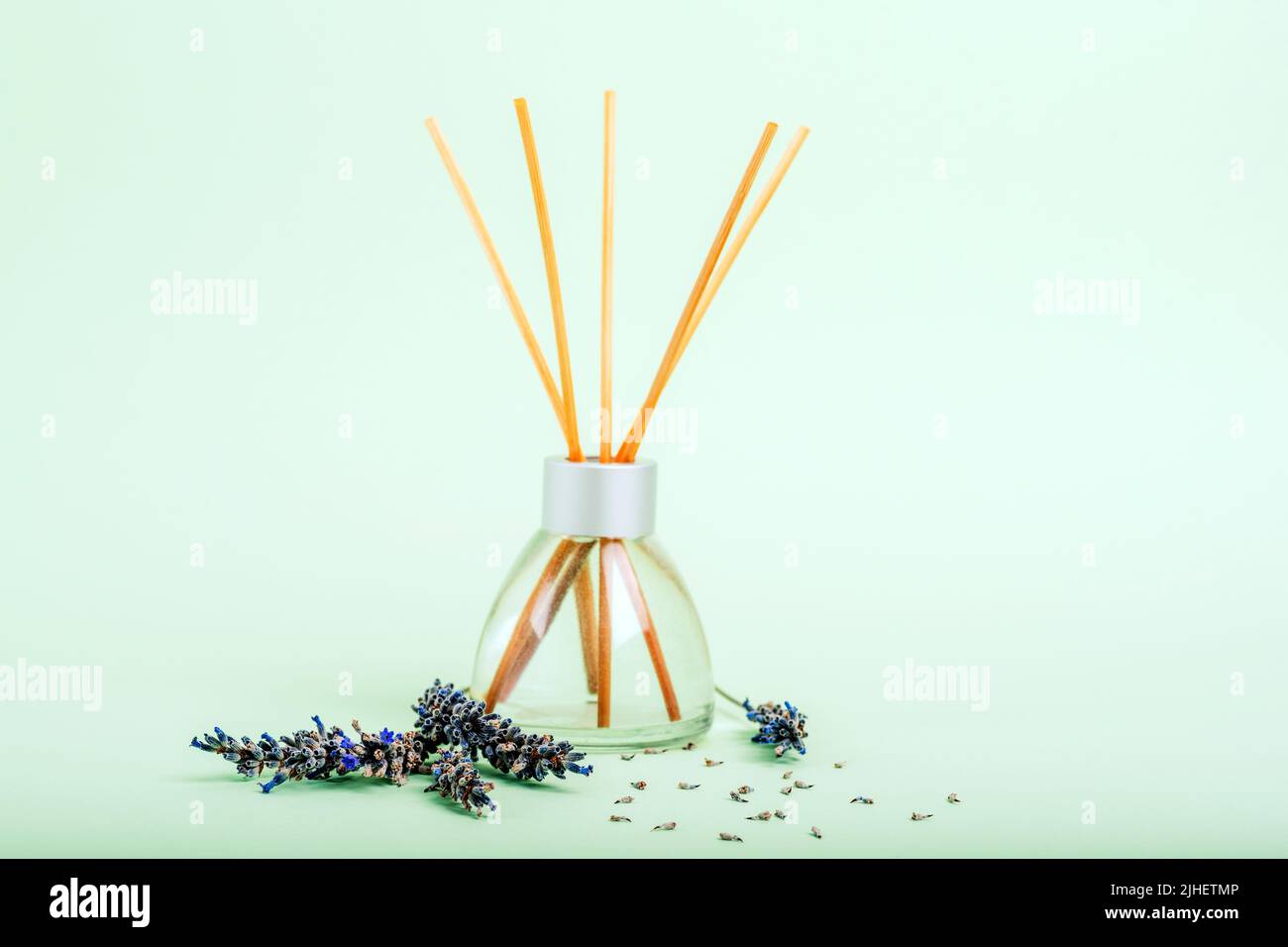 Glass bottle of reed diffuser and lavender blossom on light green ...