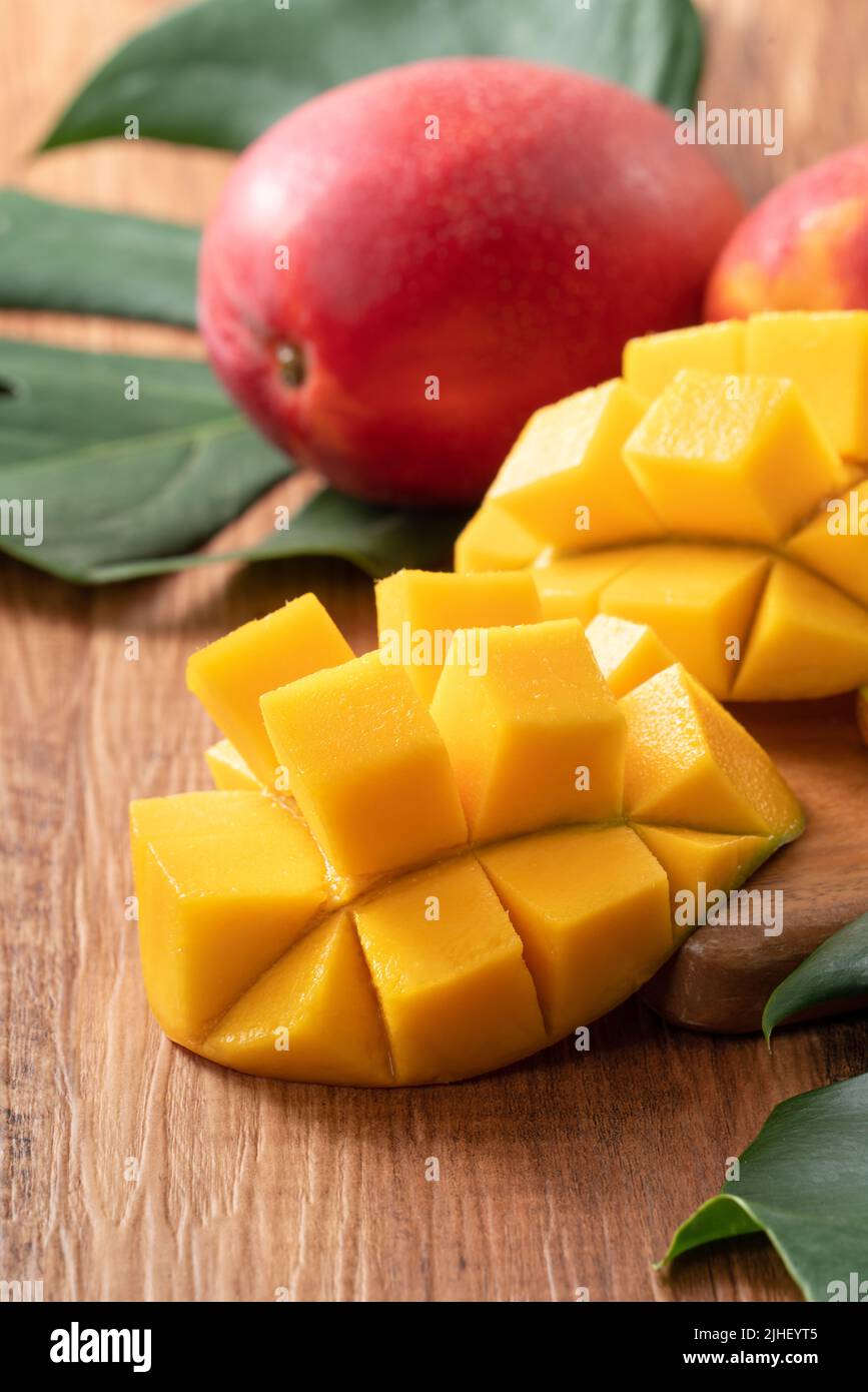 Mango. Close up of fresh ripe mango fruit with leaves over dark wooden ...