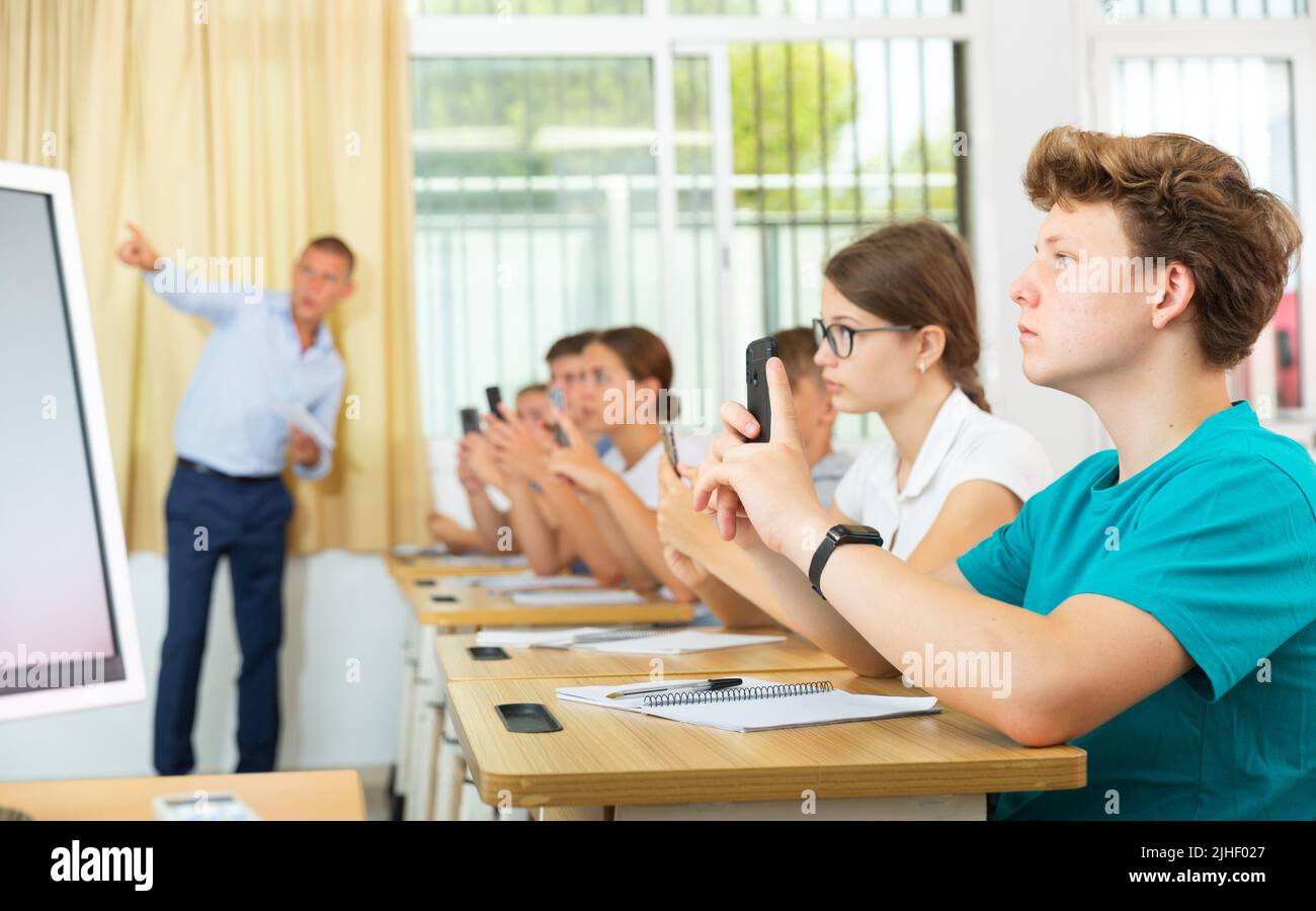 Teen student using smartphone while studying in college Stock Photo - Alamy