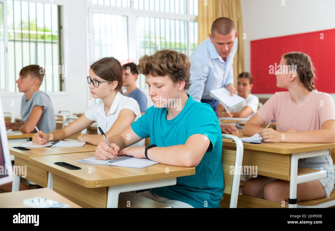Teenage students making notes of teacher lecture in class Stock Photo ...