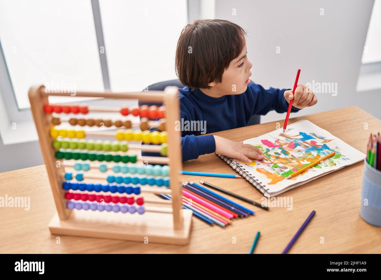 Down syndrome kid drawing on notebook at school Stock Photo - Alamy