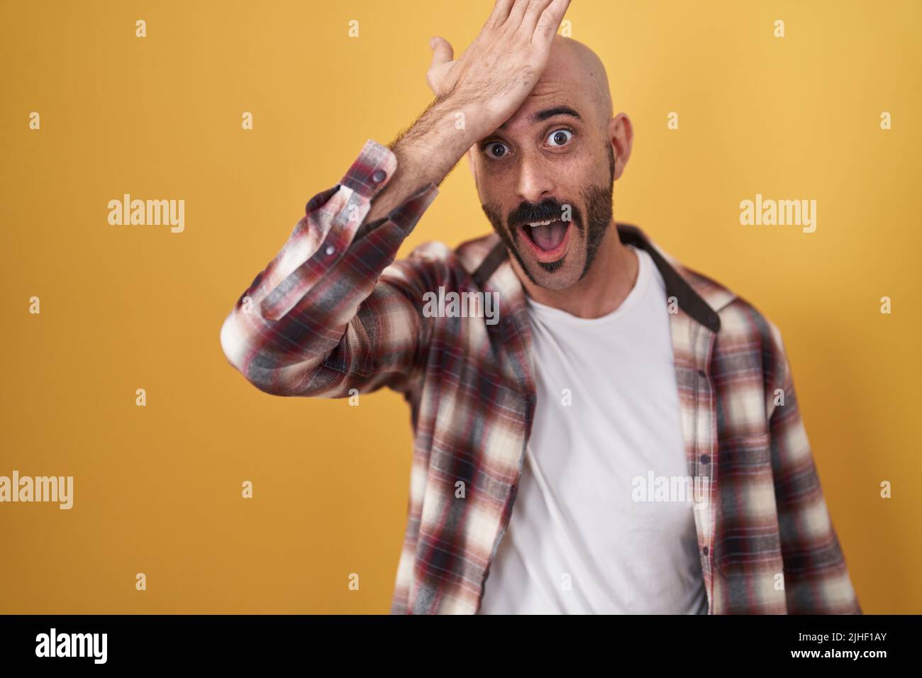 Hispanic Man With Beard Standing Over Yellow Background Surprised With
