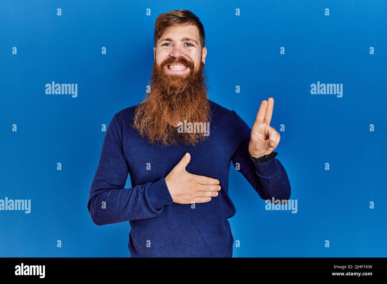 Redhead man with long beard wearing casual blue sweater over blue ...