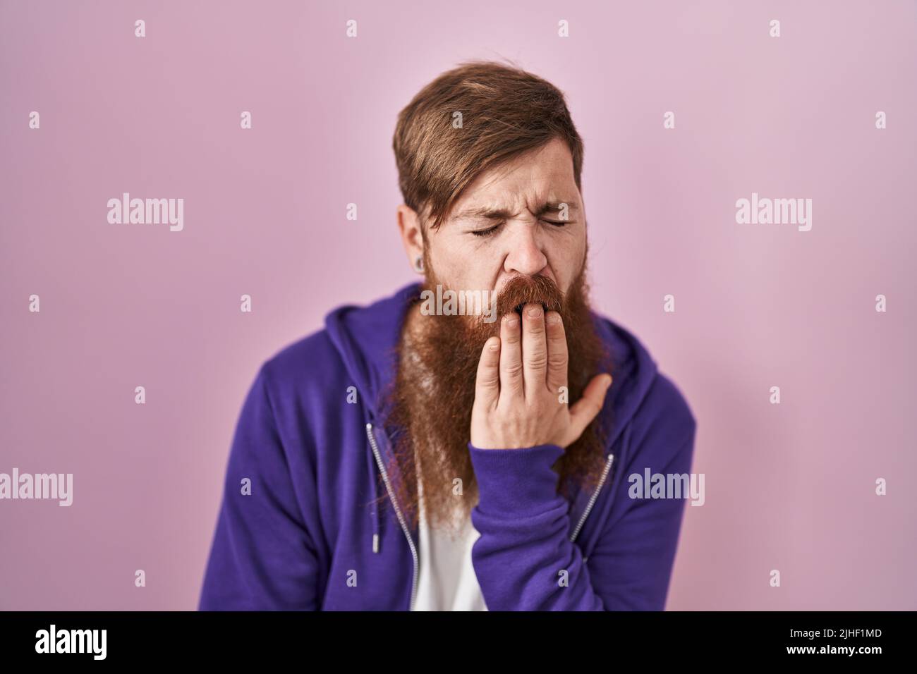 Caucasian man with long beard standing over pink background bored ...