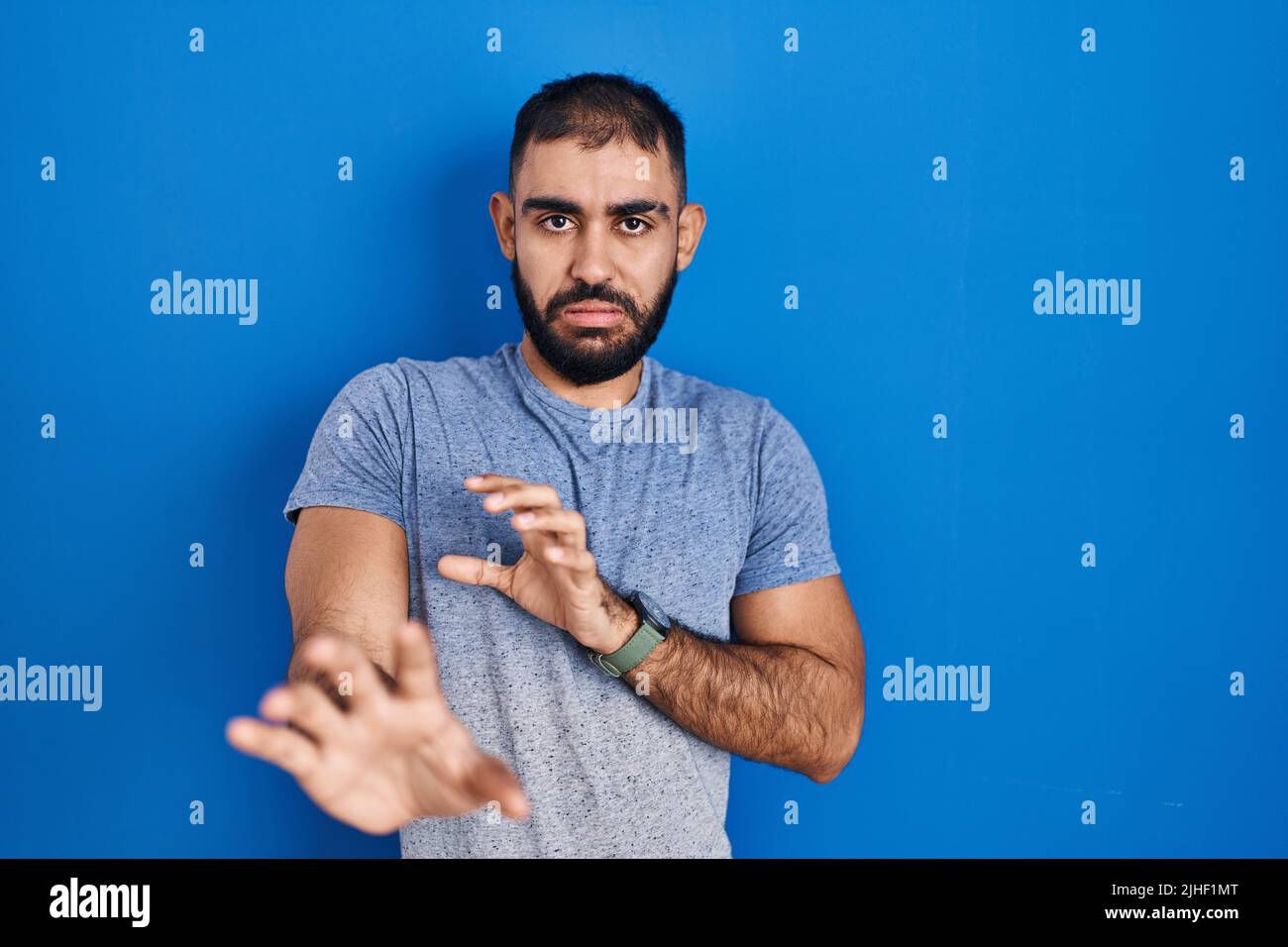 Middle east man with beard standing over blue background disgusted ...