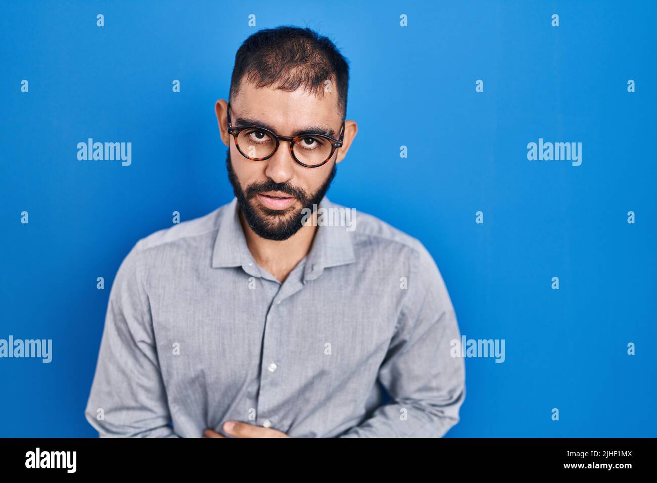 Middle East Man With Beard Standing Over Blue Background With Hand On