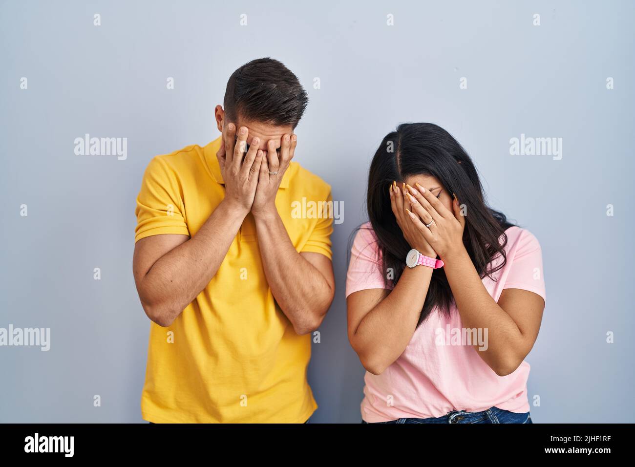 Young couple standing over isolated background with sad expression ...