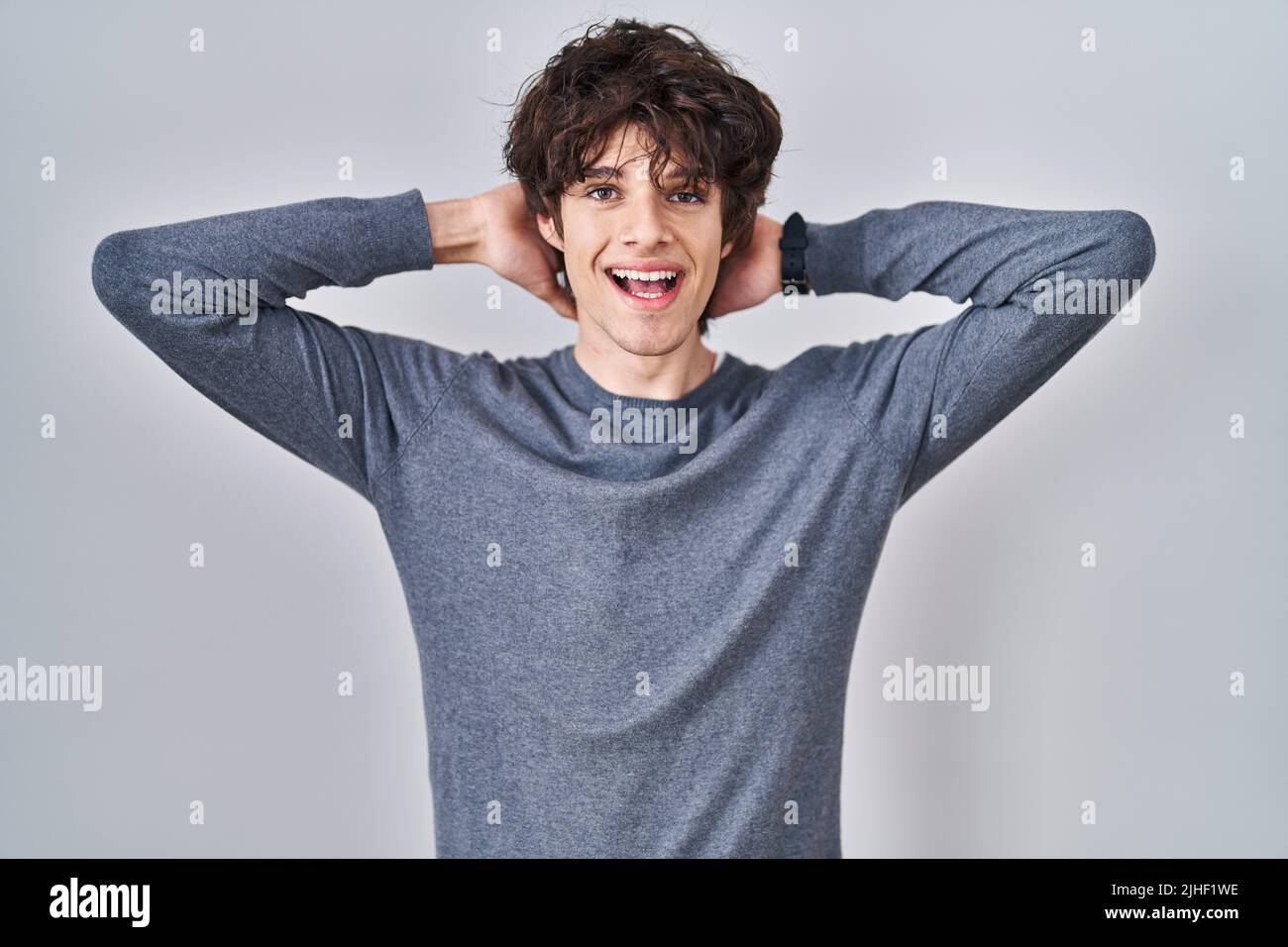 Young man standing over isolated background relaxing and stretching ...