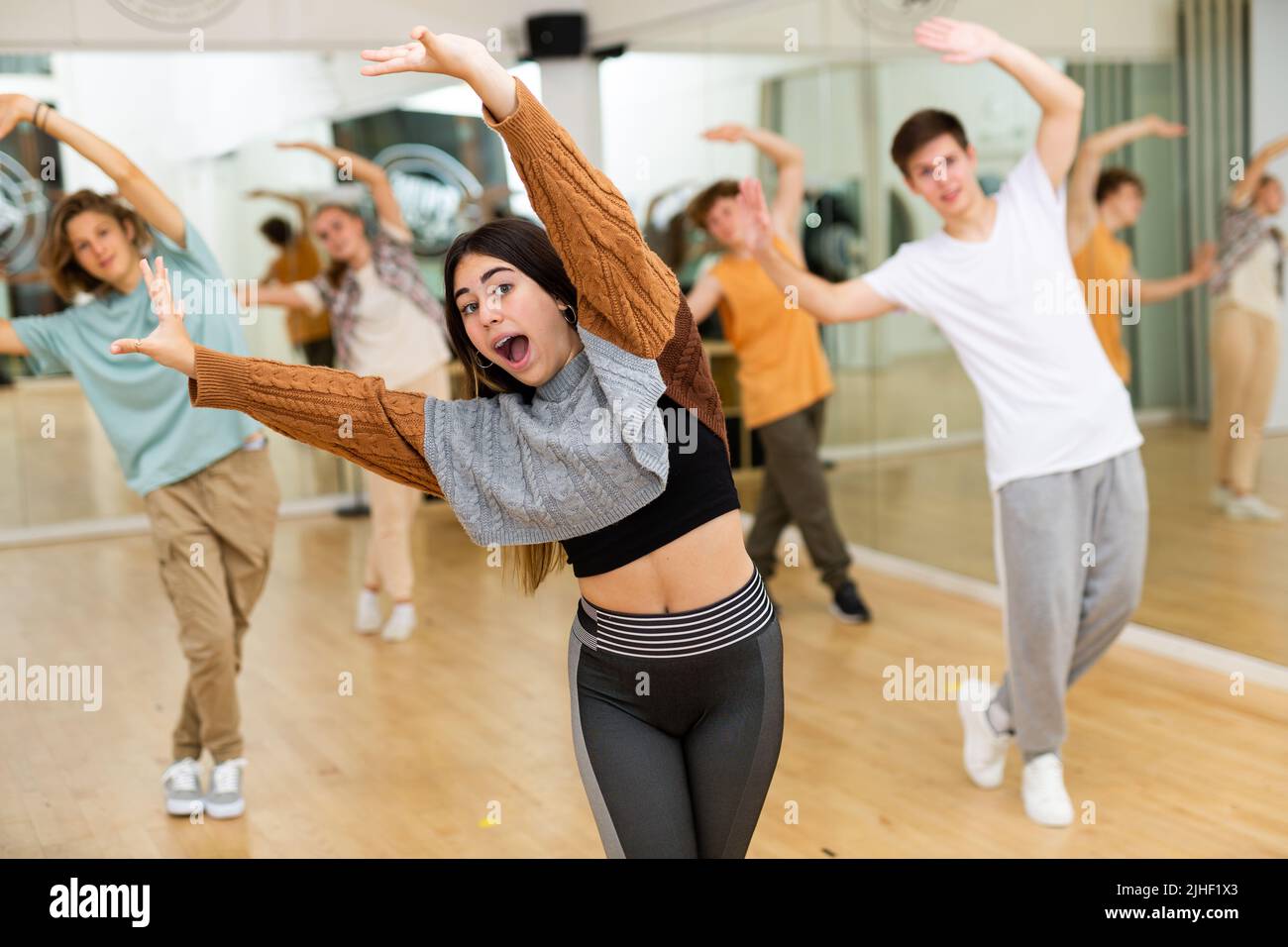 Cheerful emotional teen girl training dance movements in choreography ...