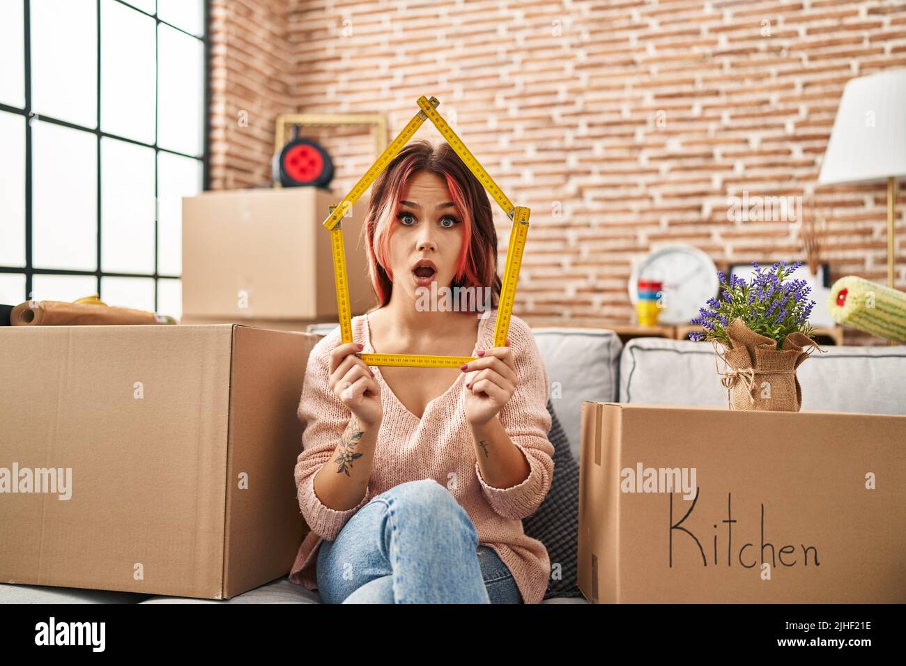 Young caucasian woman sitting on the sofa at new home afraid and ...